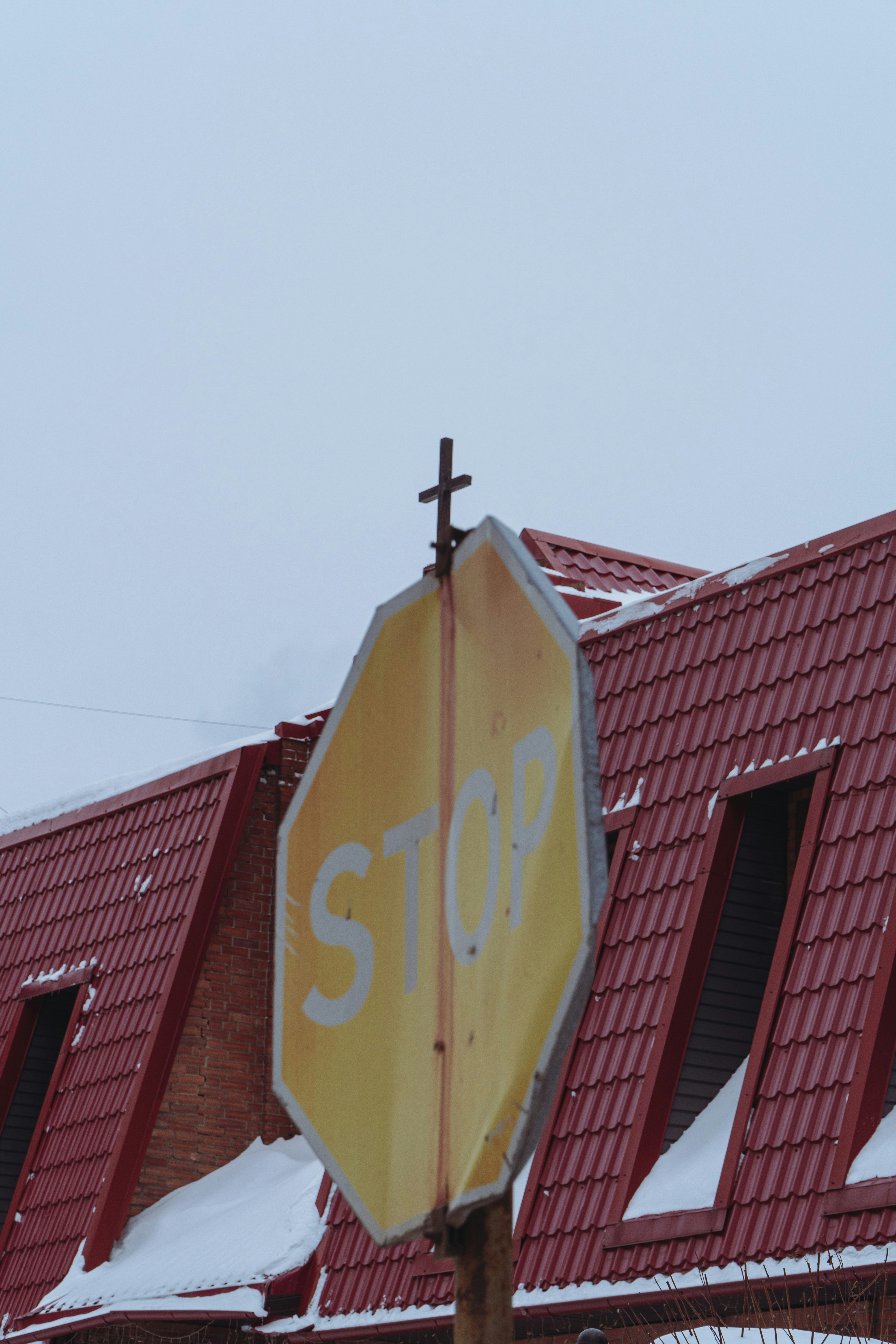 Leaning Stop Sign Framed by Crimson Rooftops in Winter Light