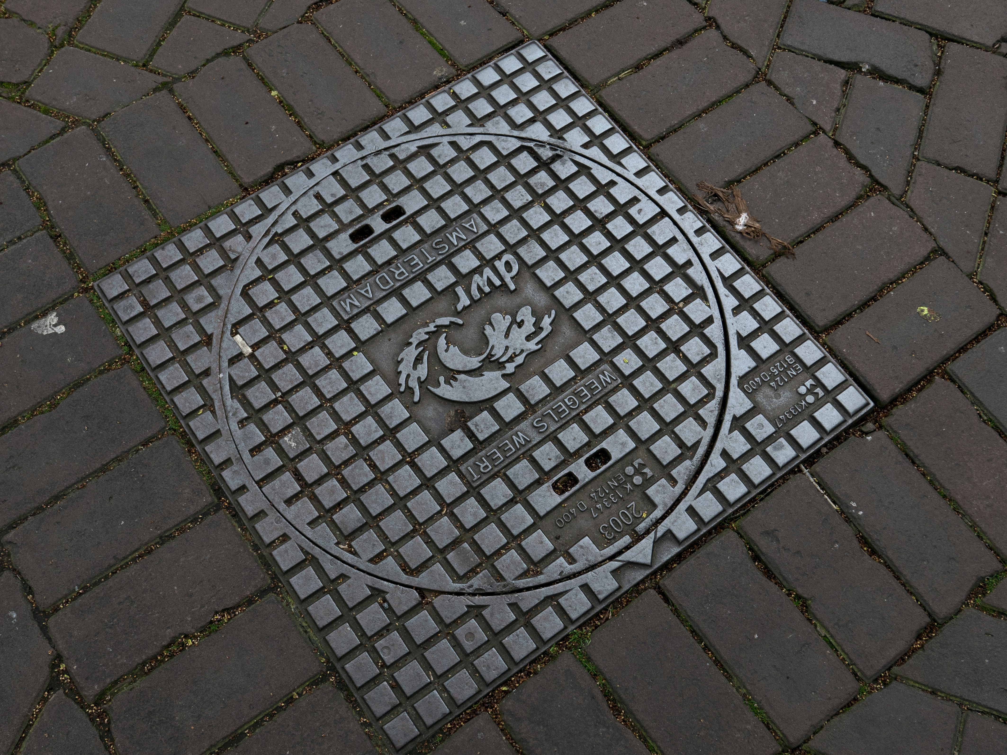 A manhole cover on a brick sidewalk photo – Free Amsterdam Image on ...