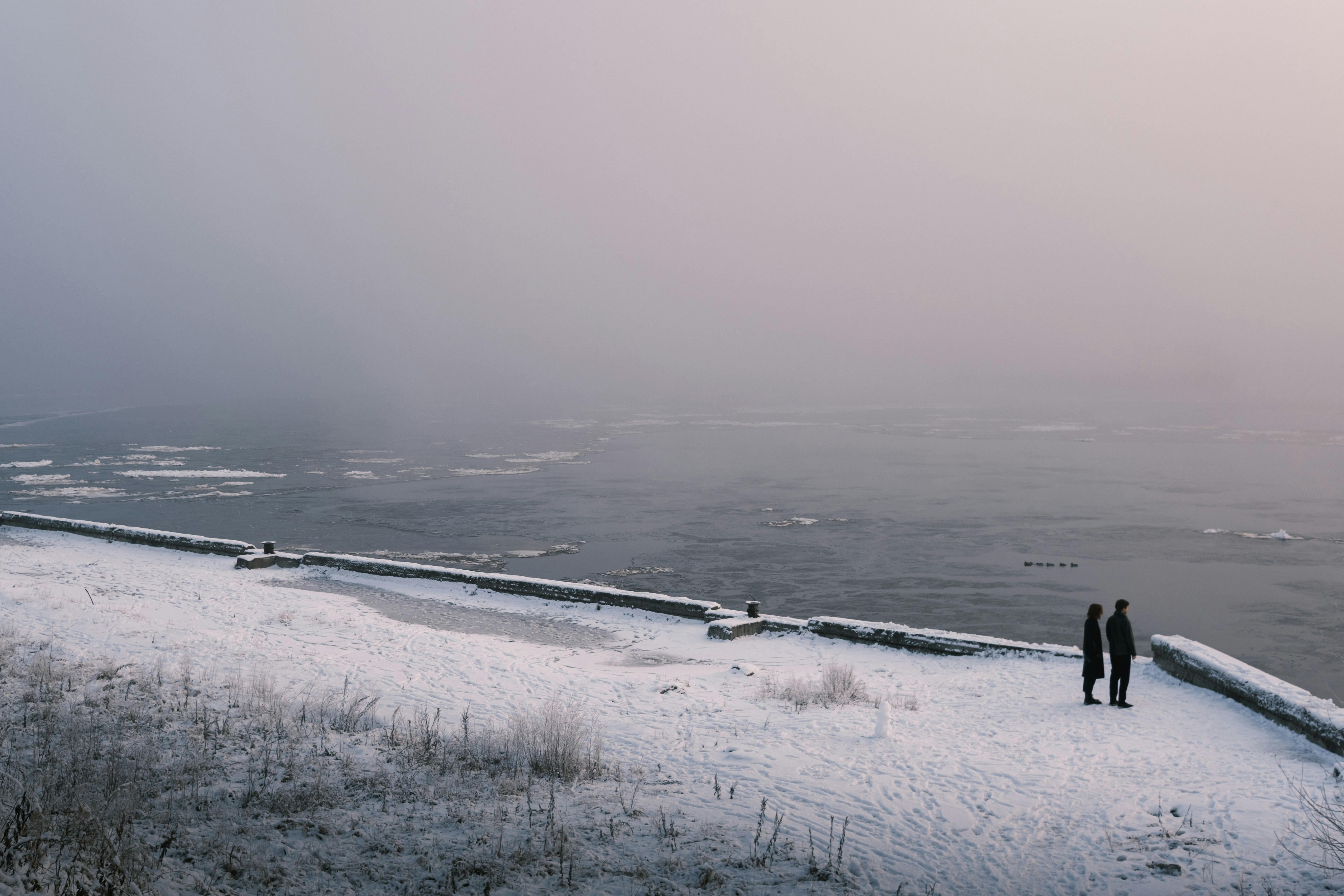 Two Figures at the Snowbound Edge: Quiet Conversation Along a Frosted Promenade