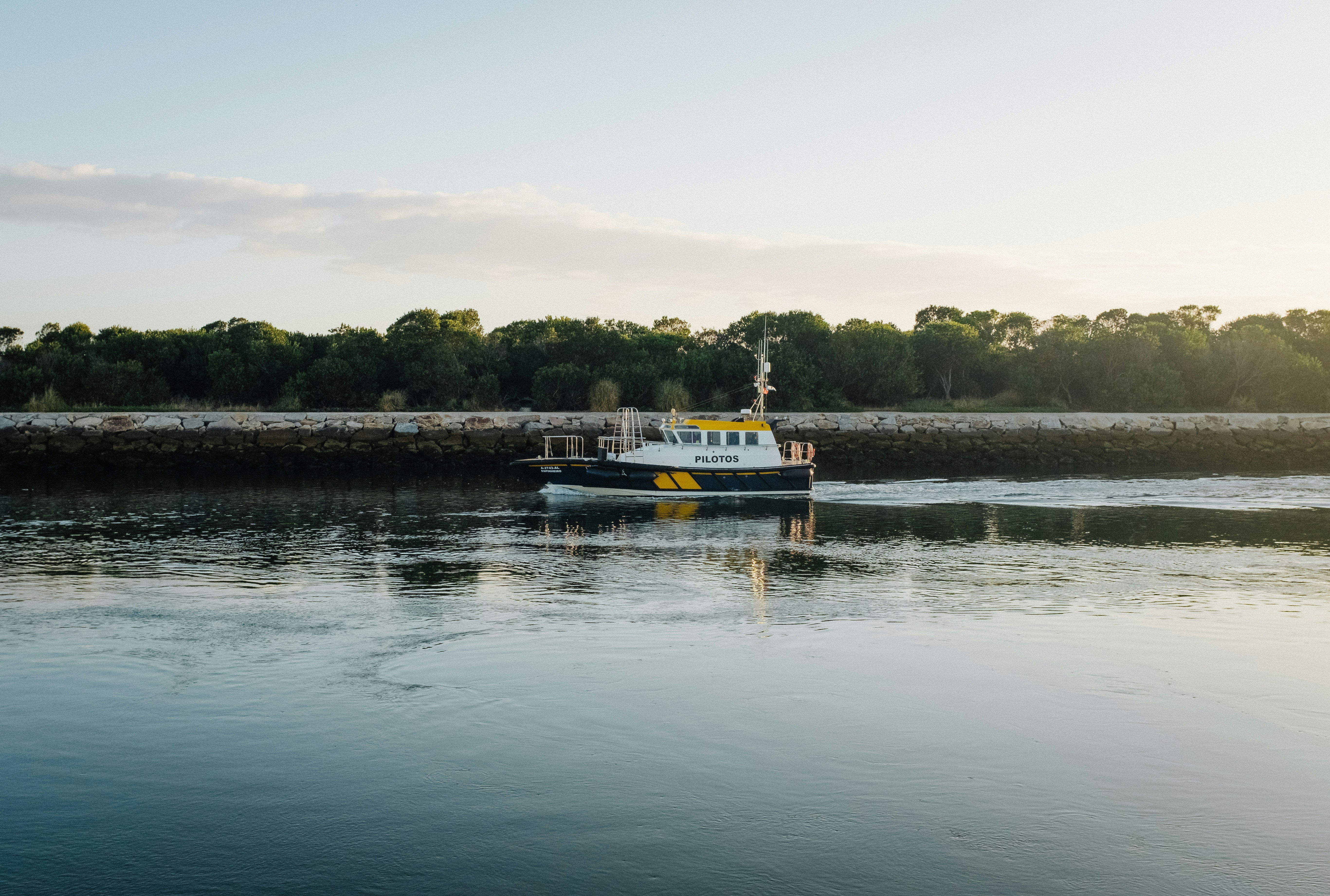 Harbor Zodiac: A lone boat resting near the breakwater at golden hour