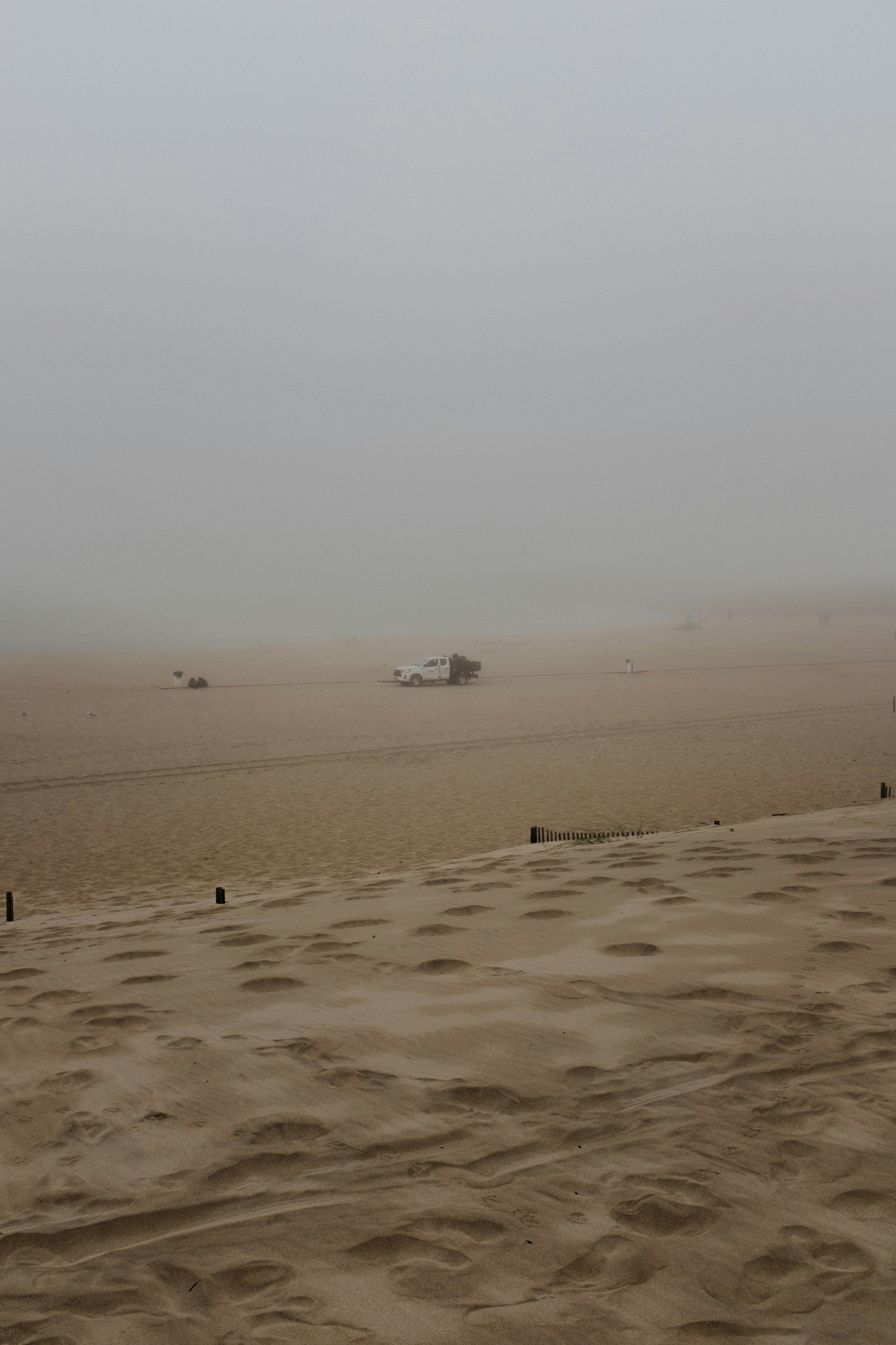 Fogbound Shoreline: A Lone White Truck Stands Against a Desolate Beach