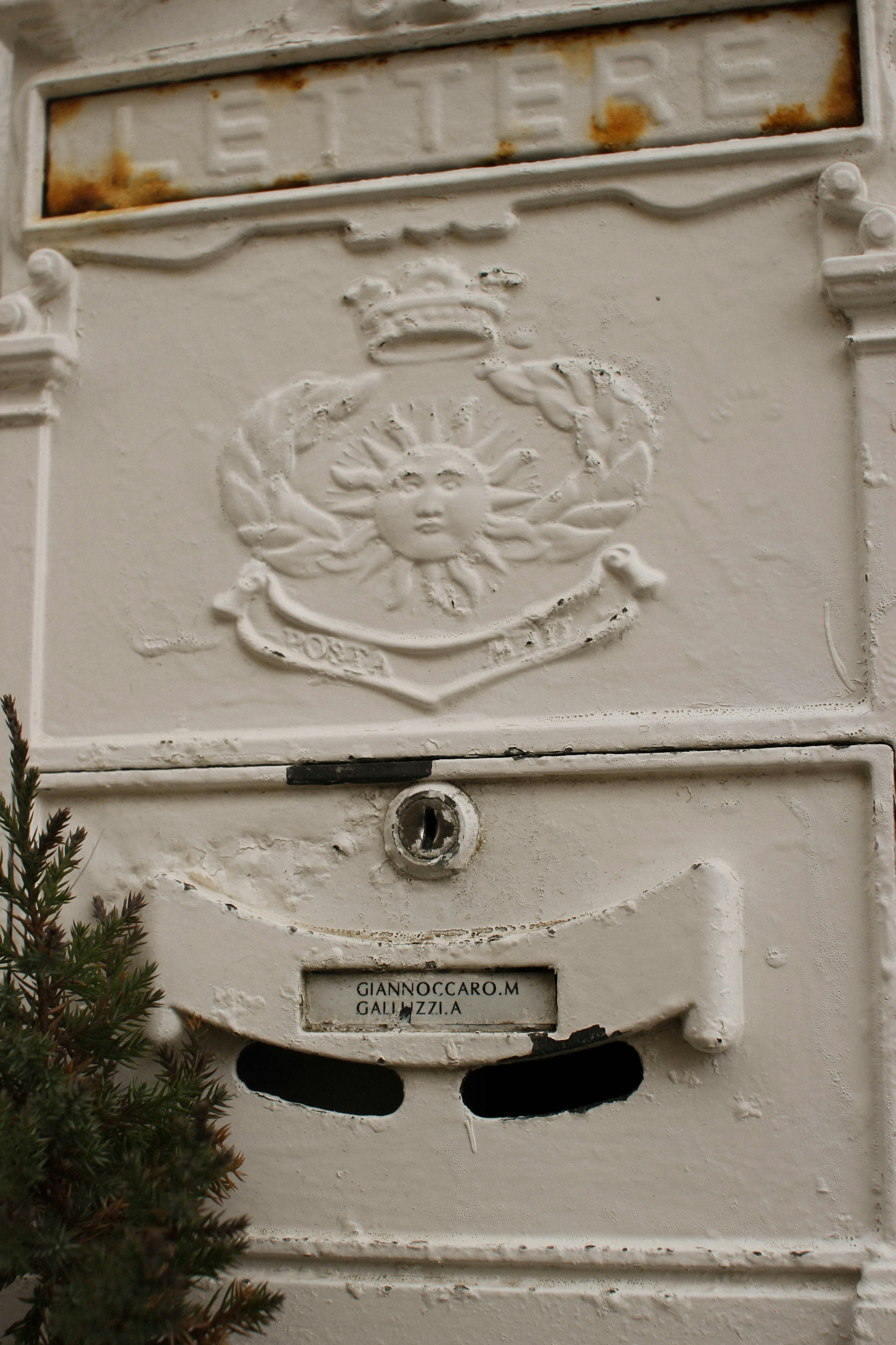 Weathered Royal Crest Mailbox: Sun Emblem and Aged Keyhole