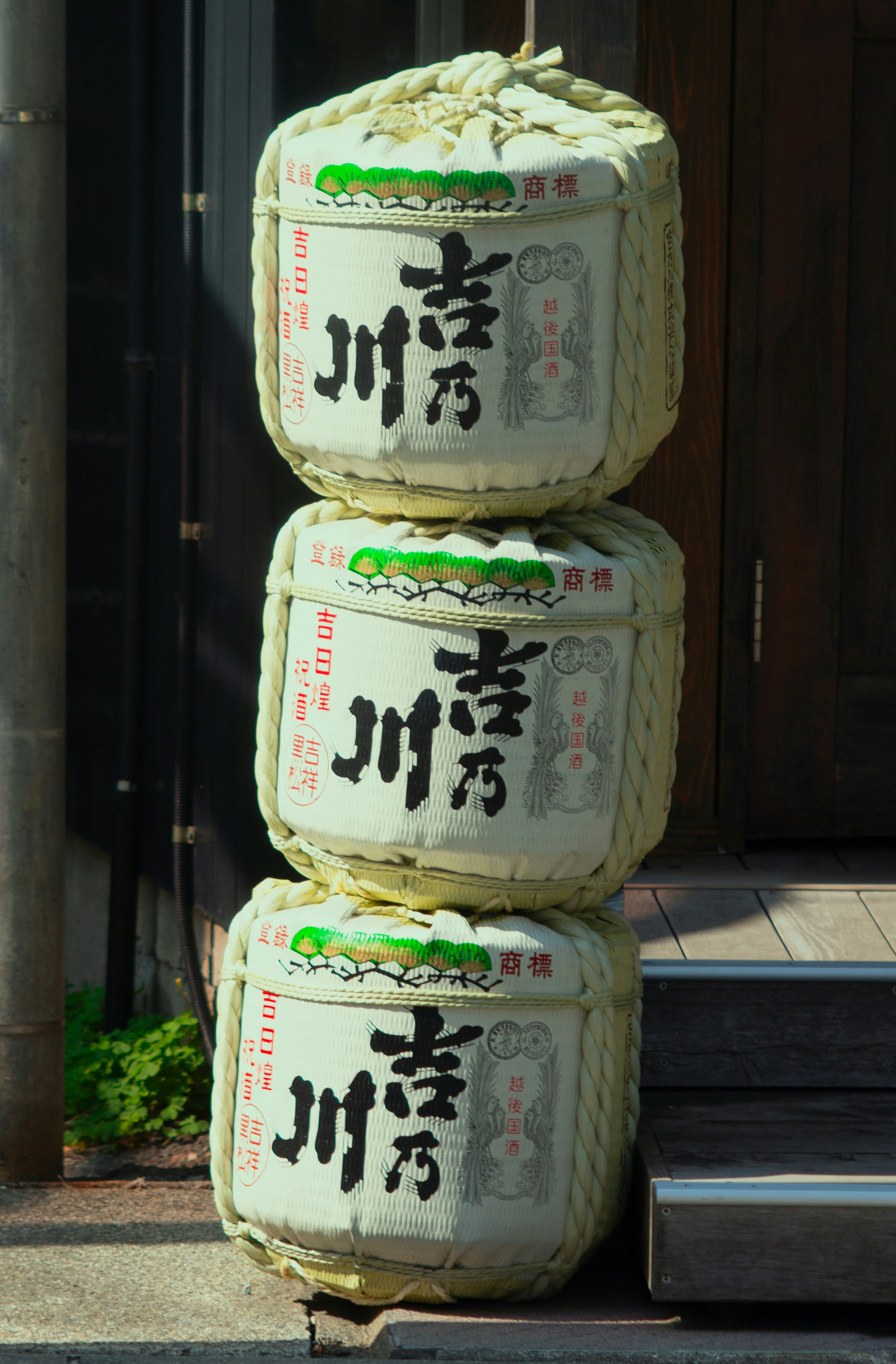Vertical Sake Barrels at a Quiet Wooden Threshold