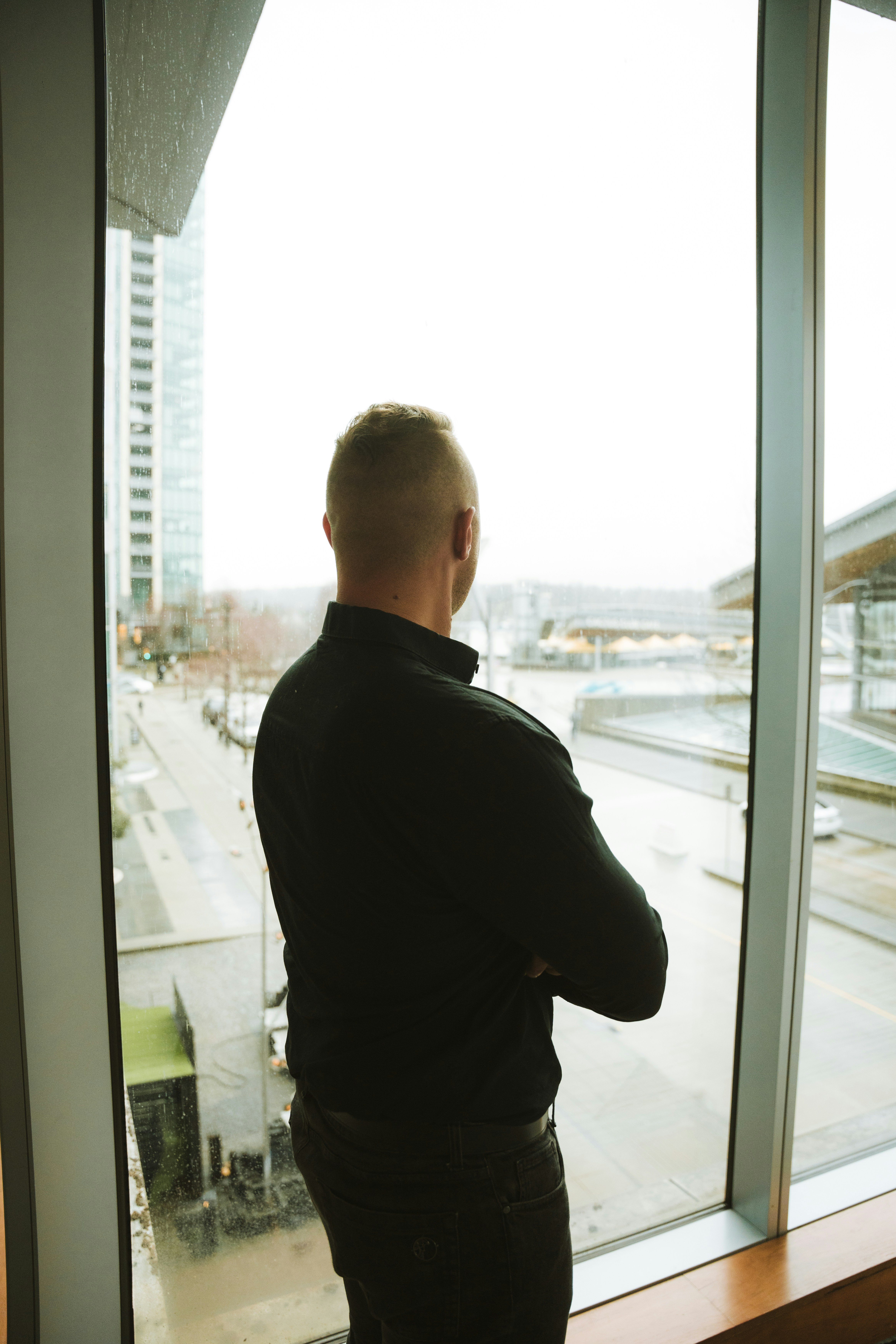 A man standing in front of a window looking out photo – Free City Image ...