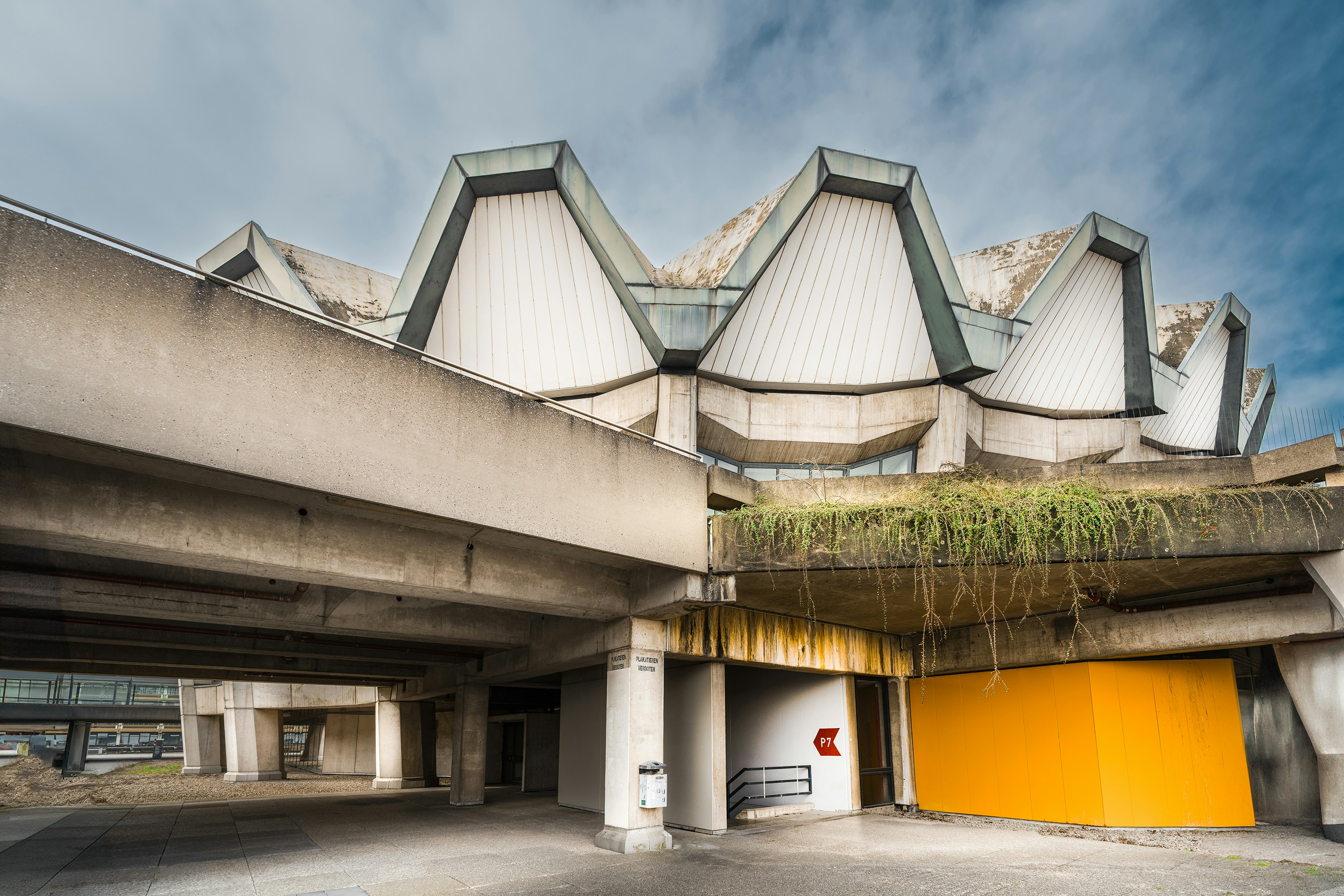 Brutalist Angles: The Orange Portal Beneath a Zigzag Roof