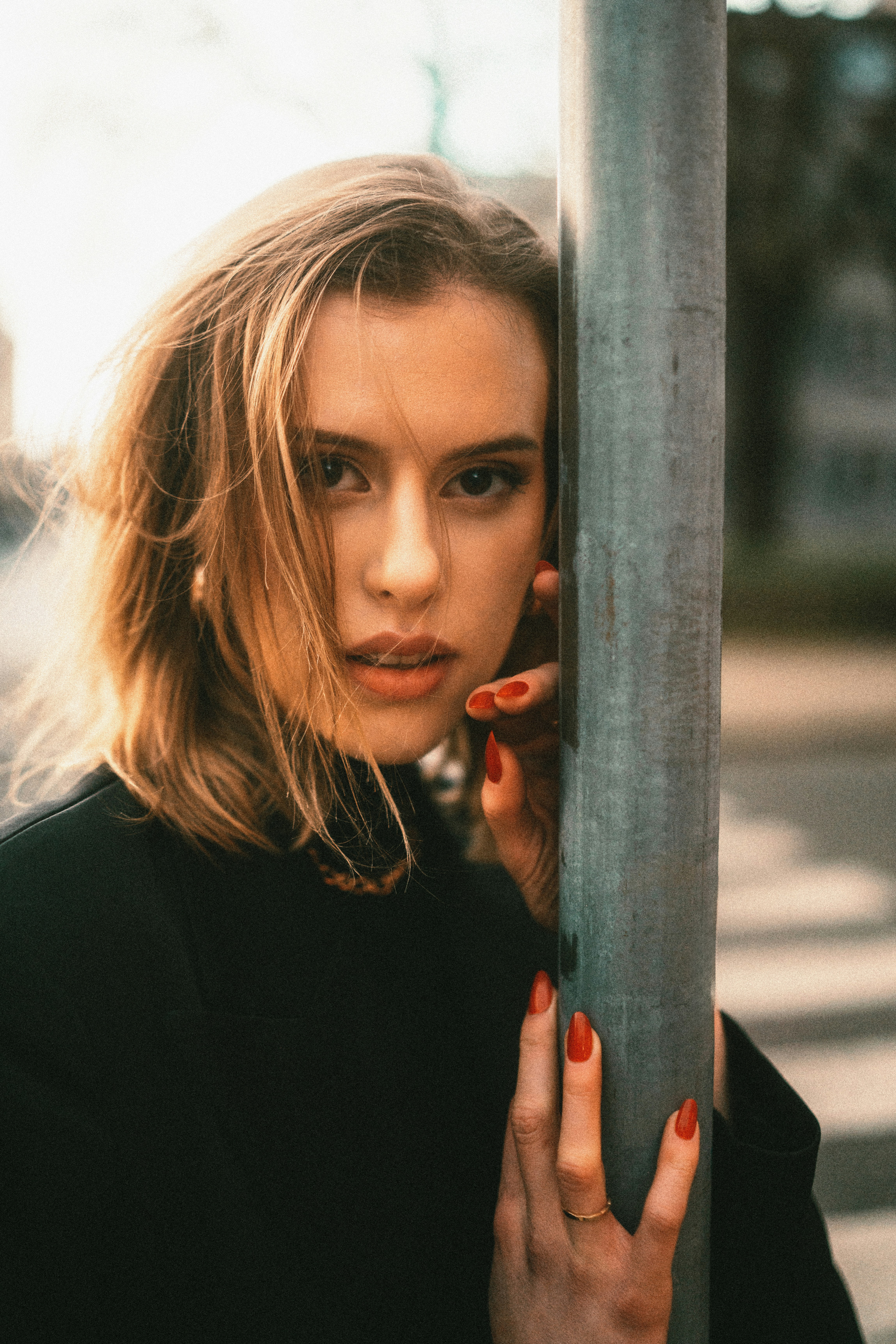 A woman leaning against a pole on a city street photo – Free Adult ...