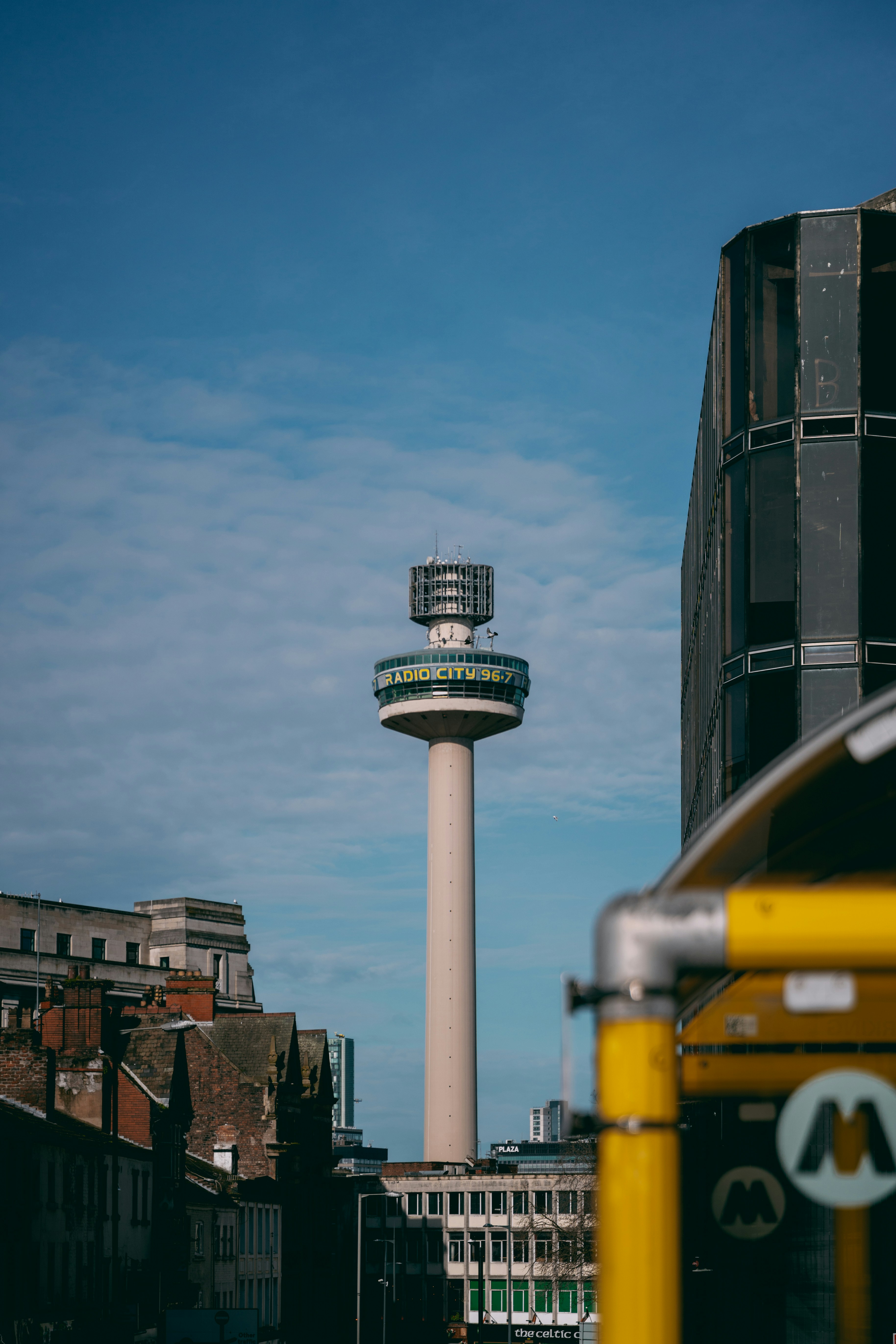 Vertical Signal Above the City: a lone radio tower framed by brick and glass