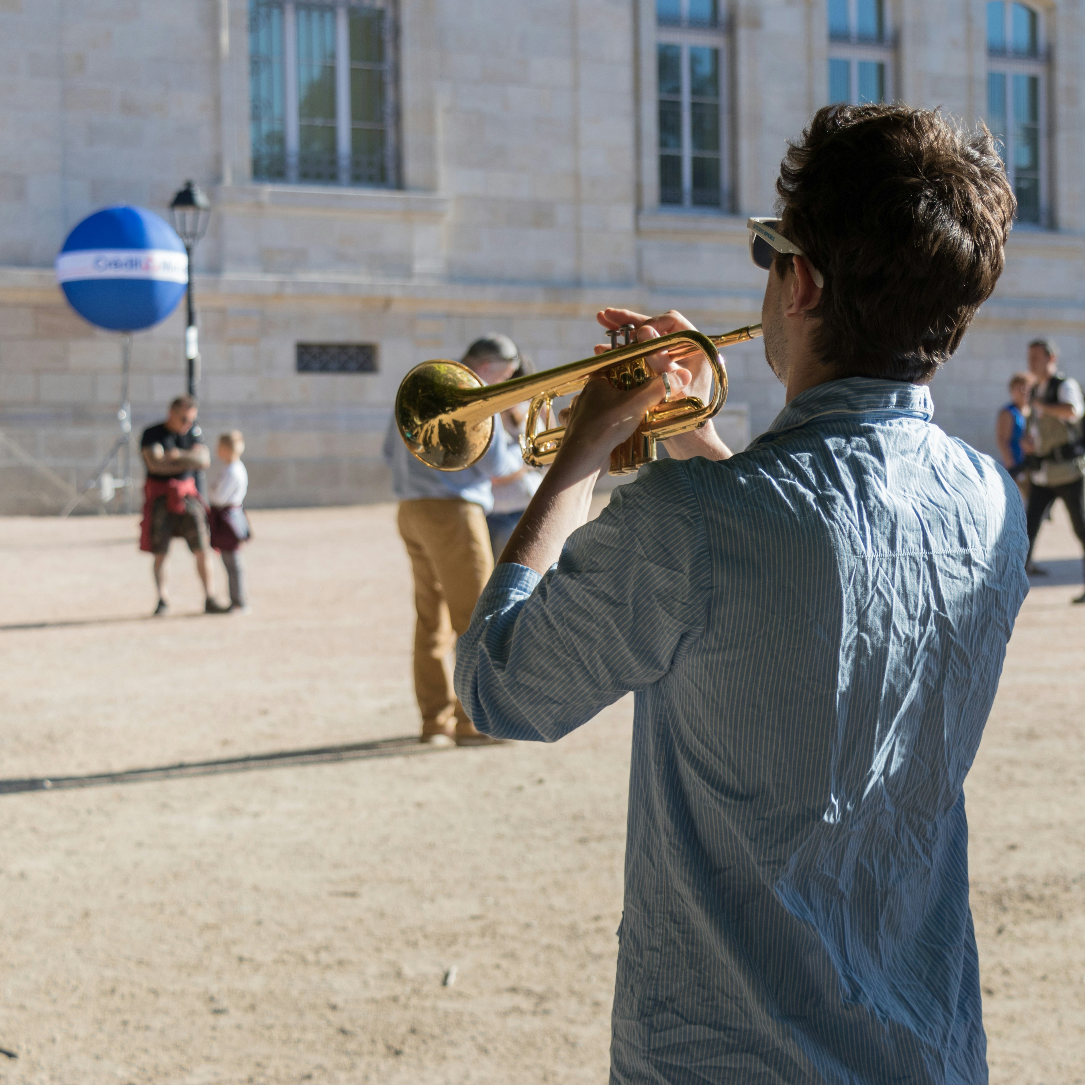 A man playing a trumpet in front of a building photo – Free Human Image ...