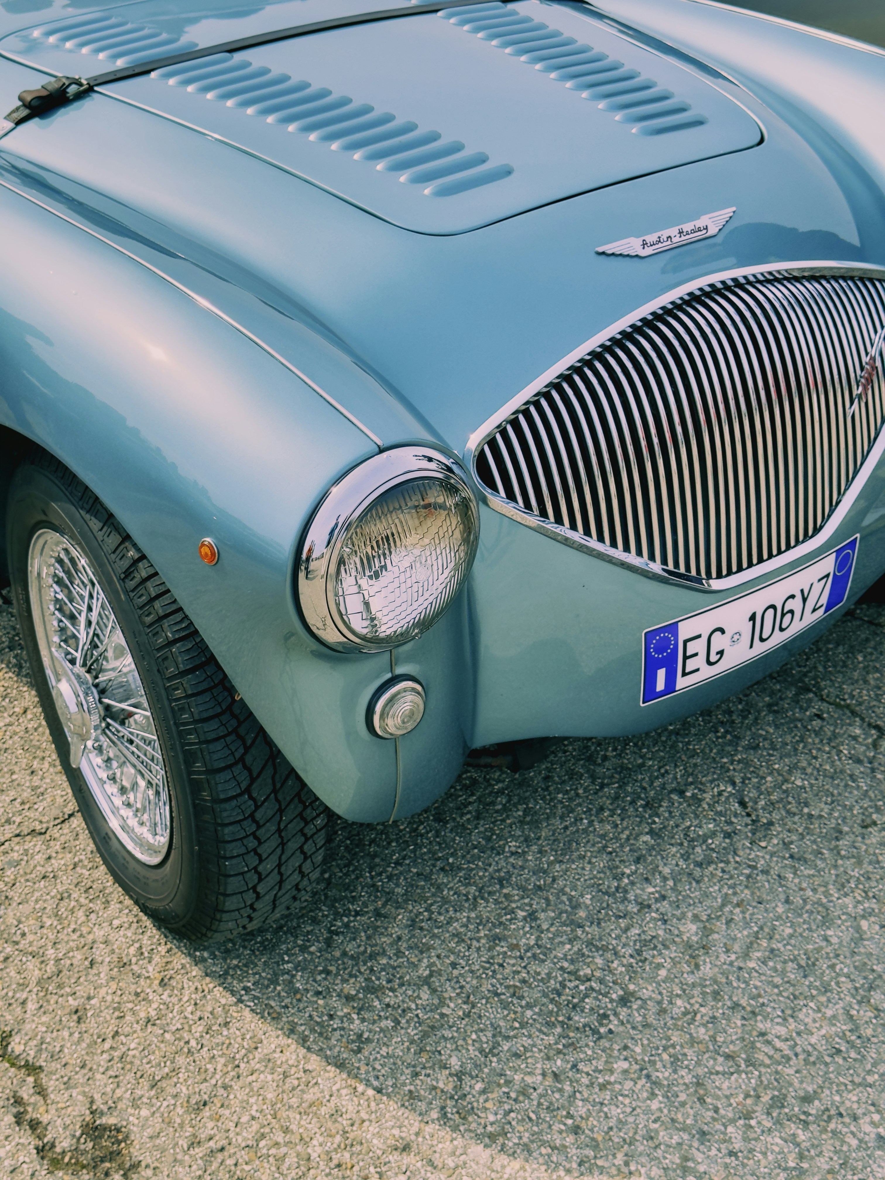 Blue vintage car with prominent chrome grille and rounded headlamp, showcasing classic design details and a European license plate.