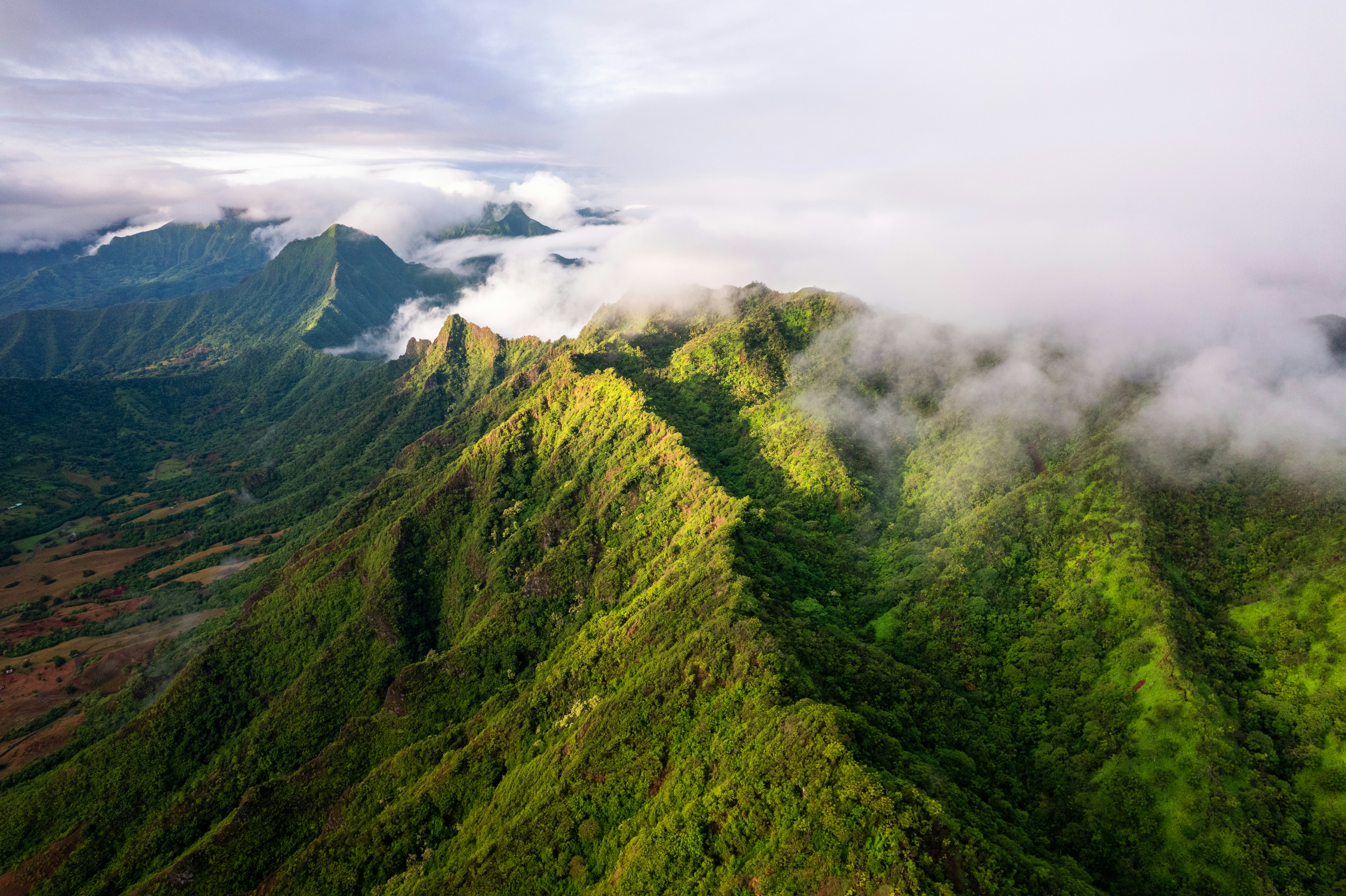 Lush green mountains bathed in sunlight, partially veiled by drifting clouds.
