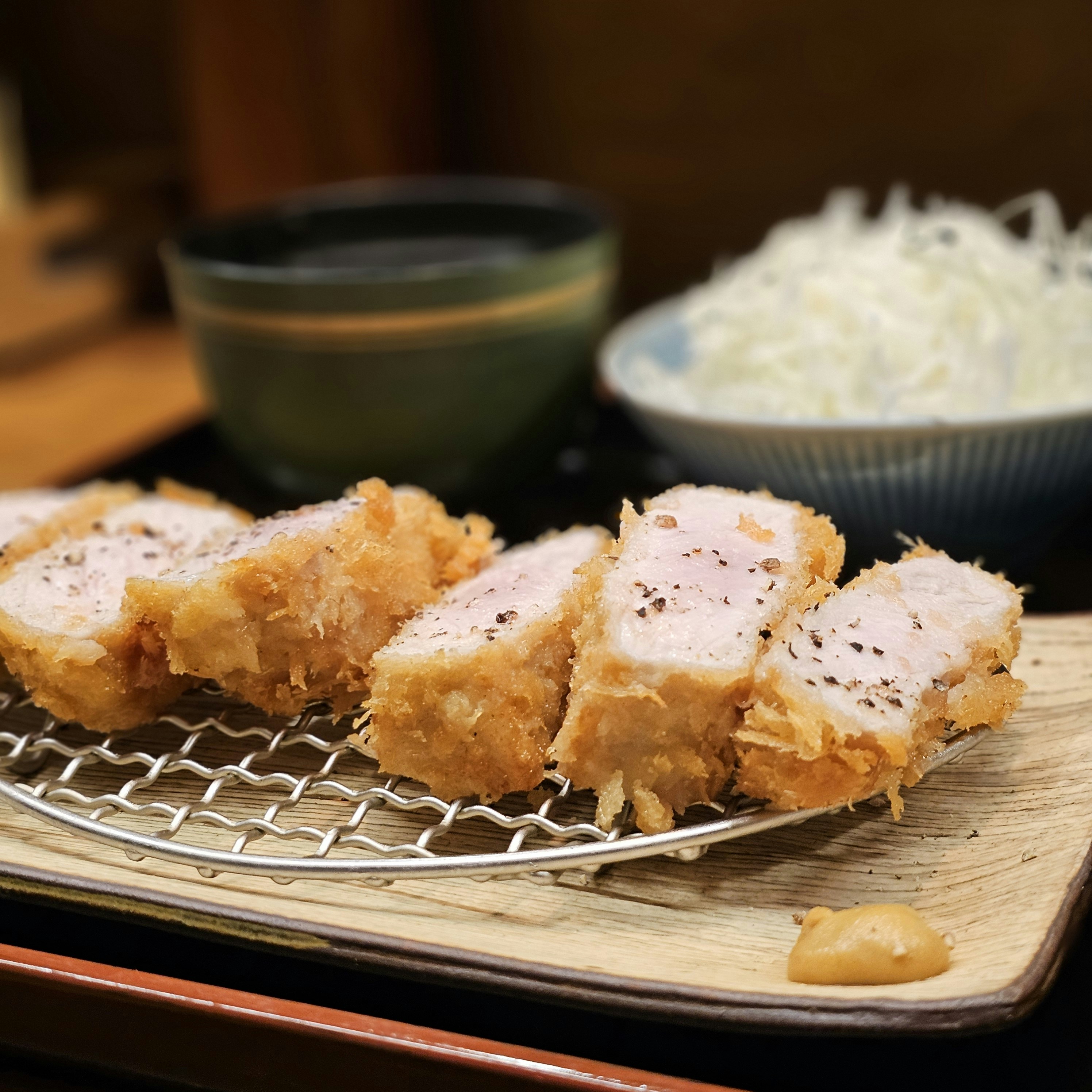 Golden Tonkatsu Slices on a Wire Rack, with Cabbage Backdrop