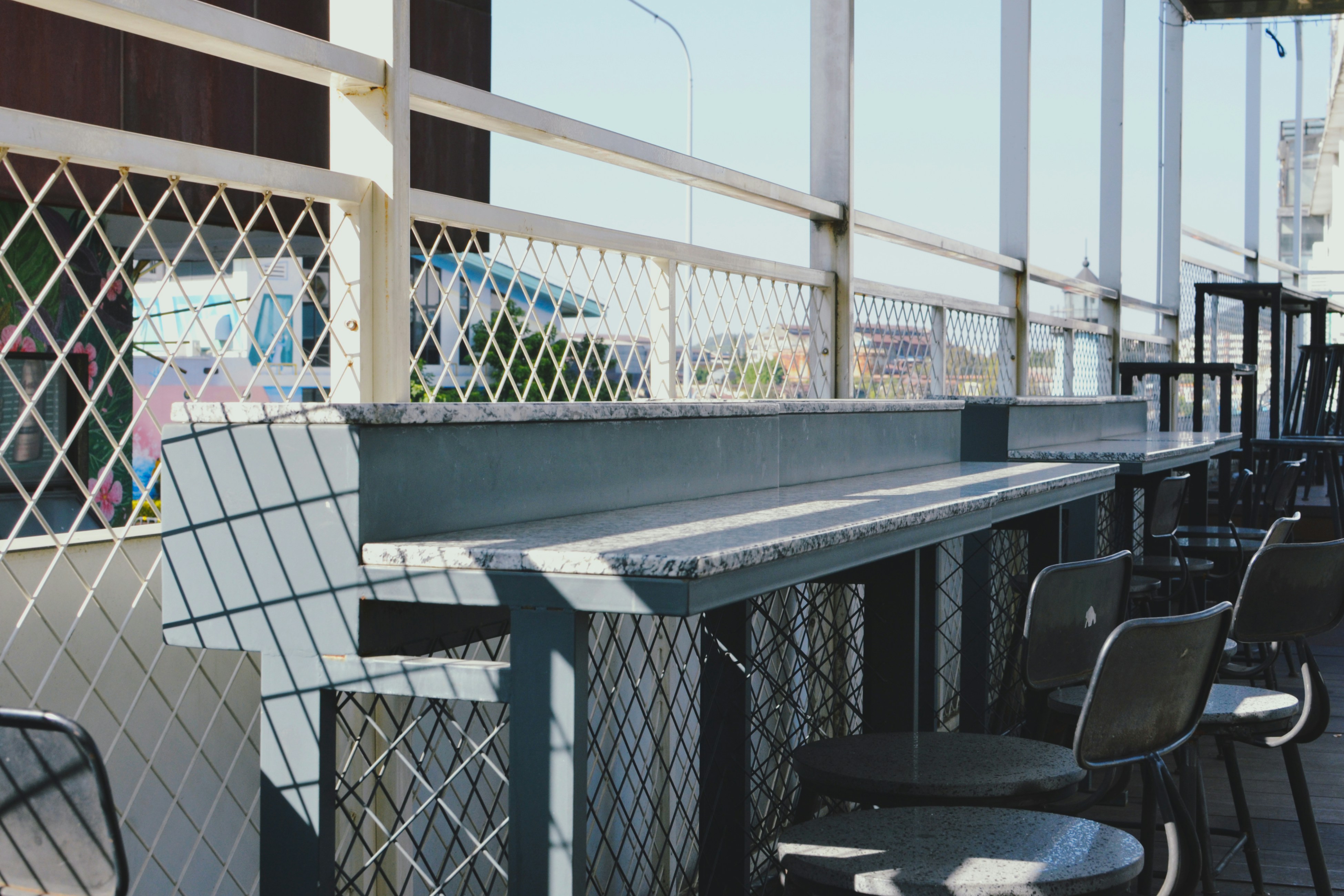 Sunlit Row of Benches by the Fence in an Empty Stadium Concourse