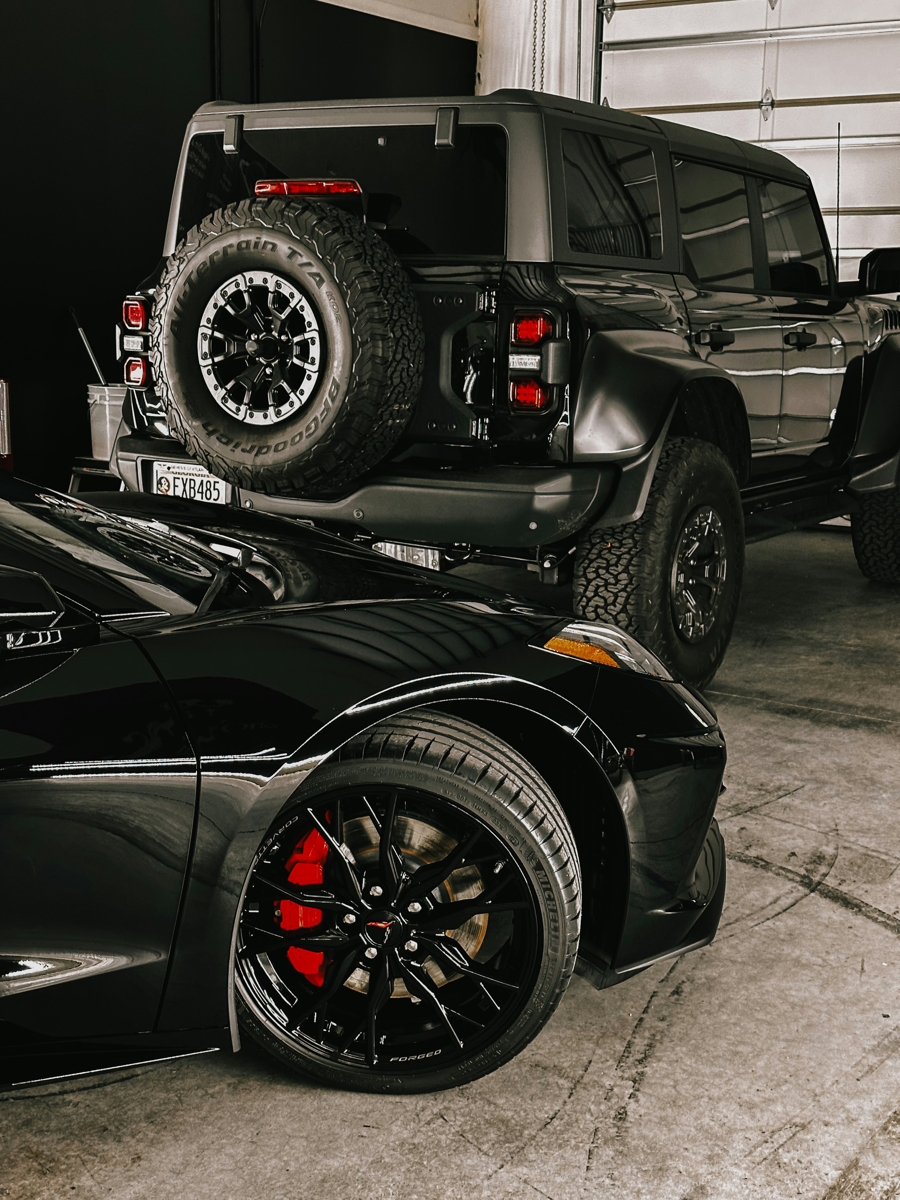 Monochrome Showroom: A Sleek Coupe Commands a Quiet Garage Against a Rugged SUV