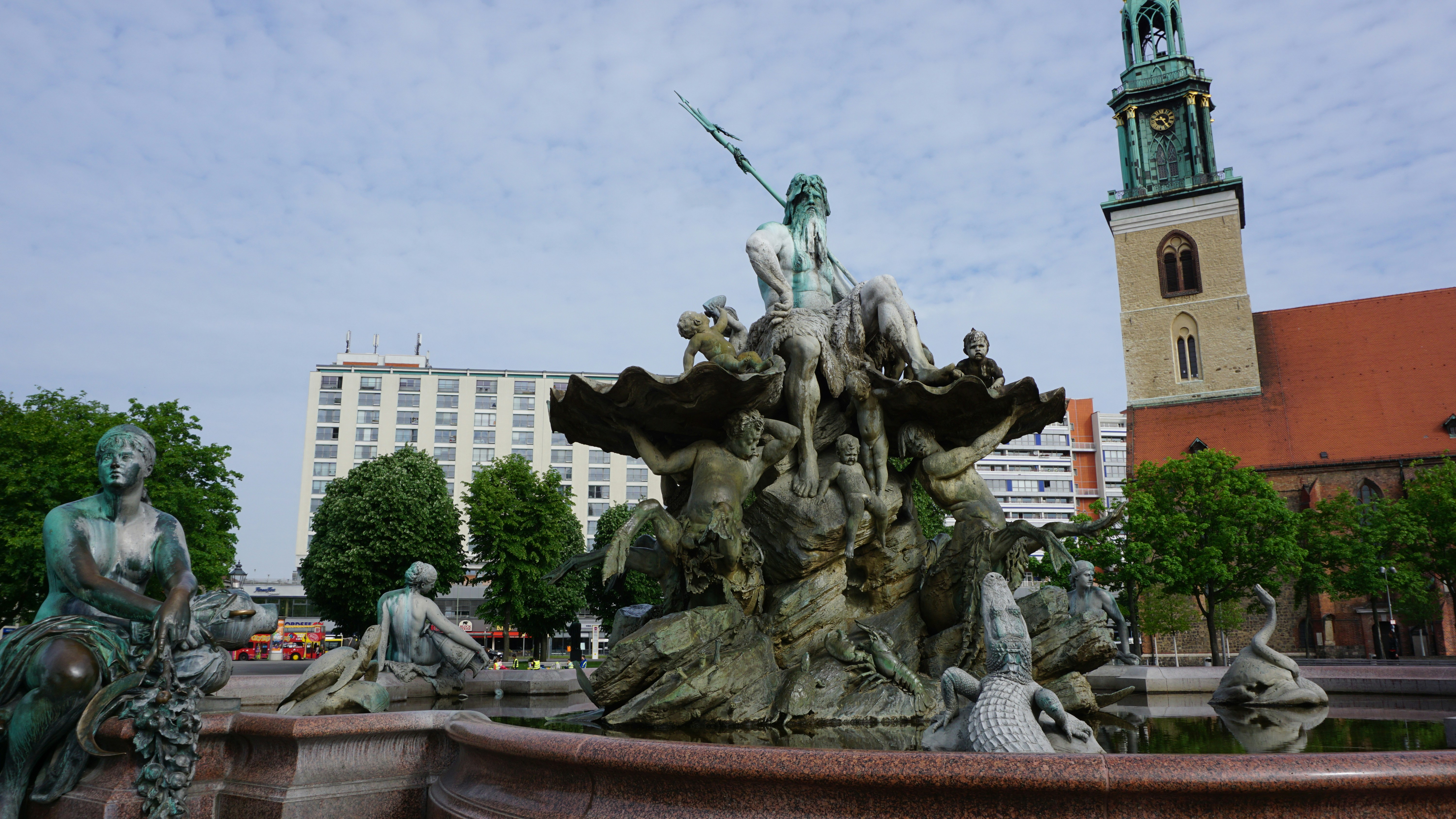 A fountain with statues and a clock tower in the background photo ...