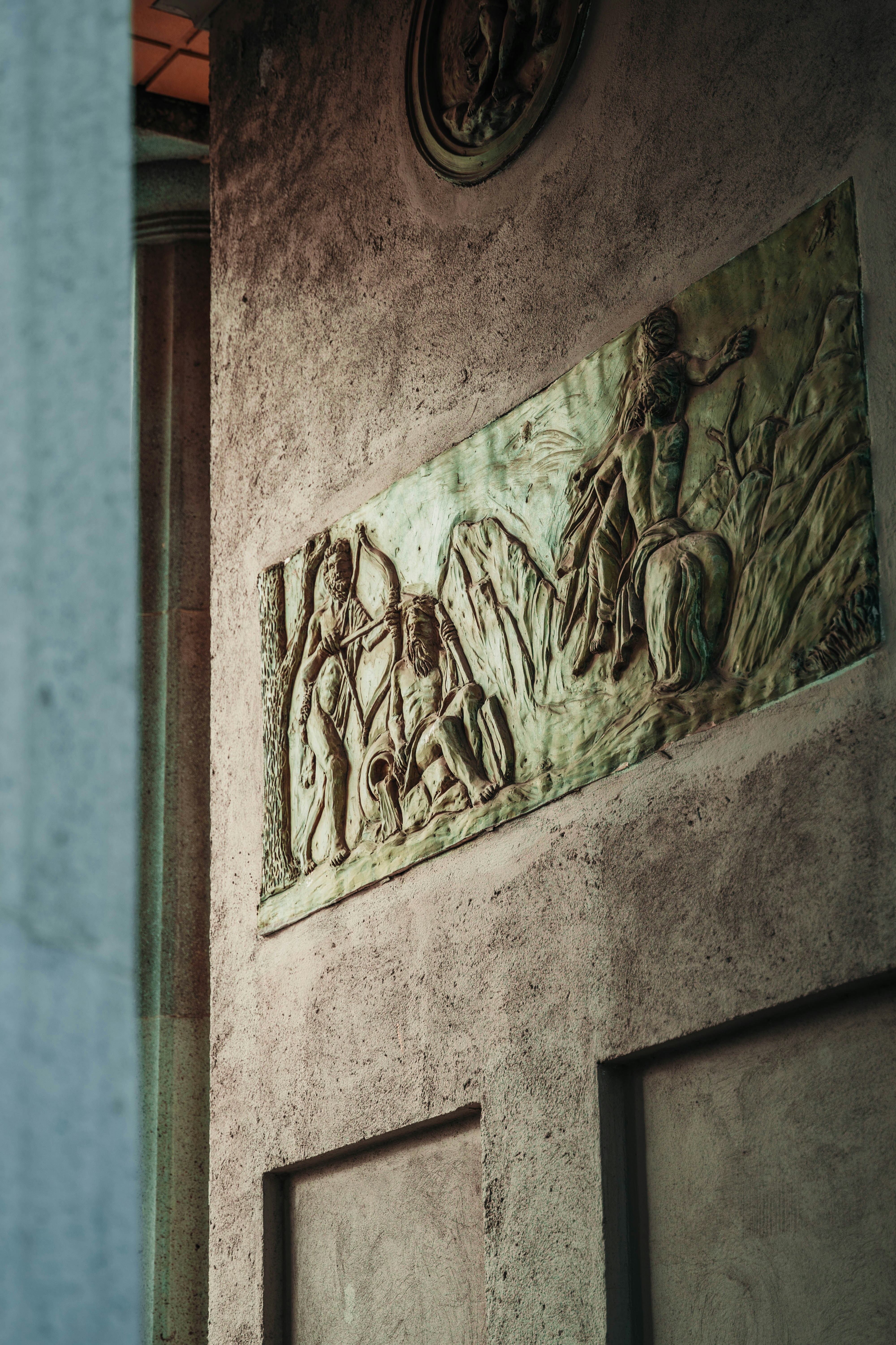 Relief sculpture depicting heroic figures on horseback against a mountainous backdrop. The artwork showcases intricate details and craftsmanship.