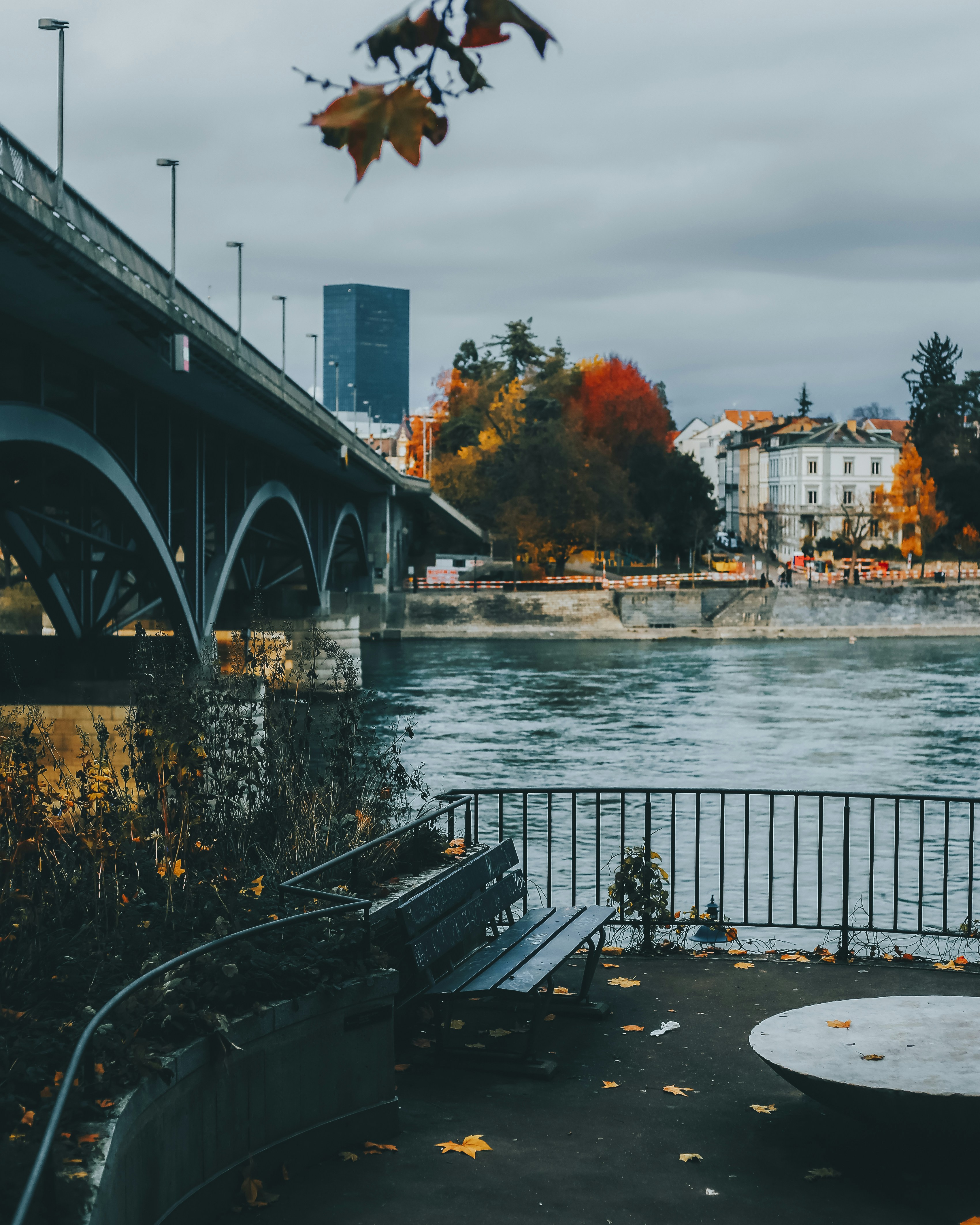 A bench sitting on the side of a river next to a bridge photo – Free ...