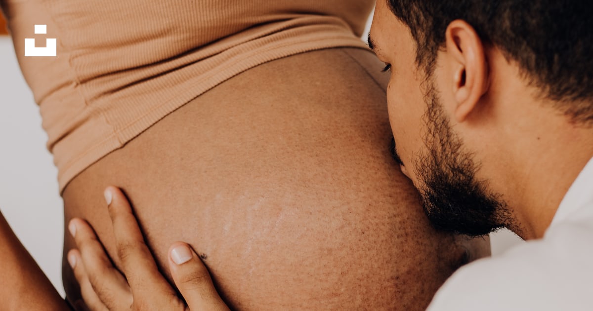 임신한 남자가 배를 잡고 있는 동안 여자가 그를 바라보고 있다 사진 Unsplash의 무료 초상 이미지