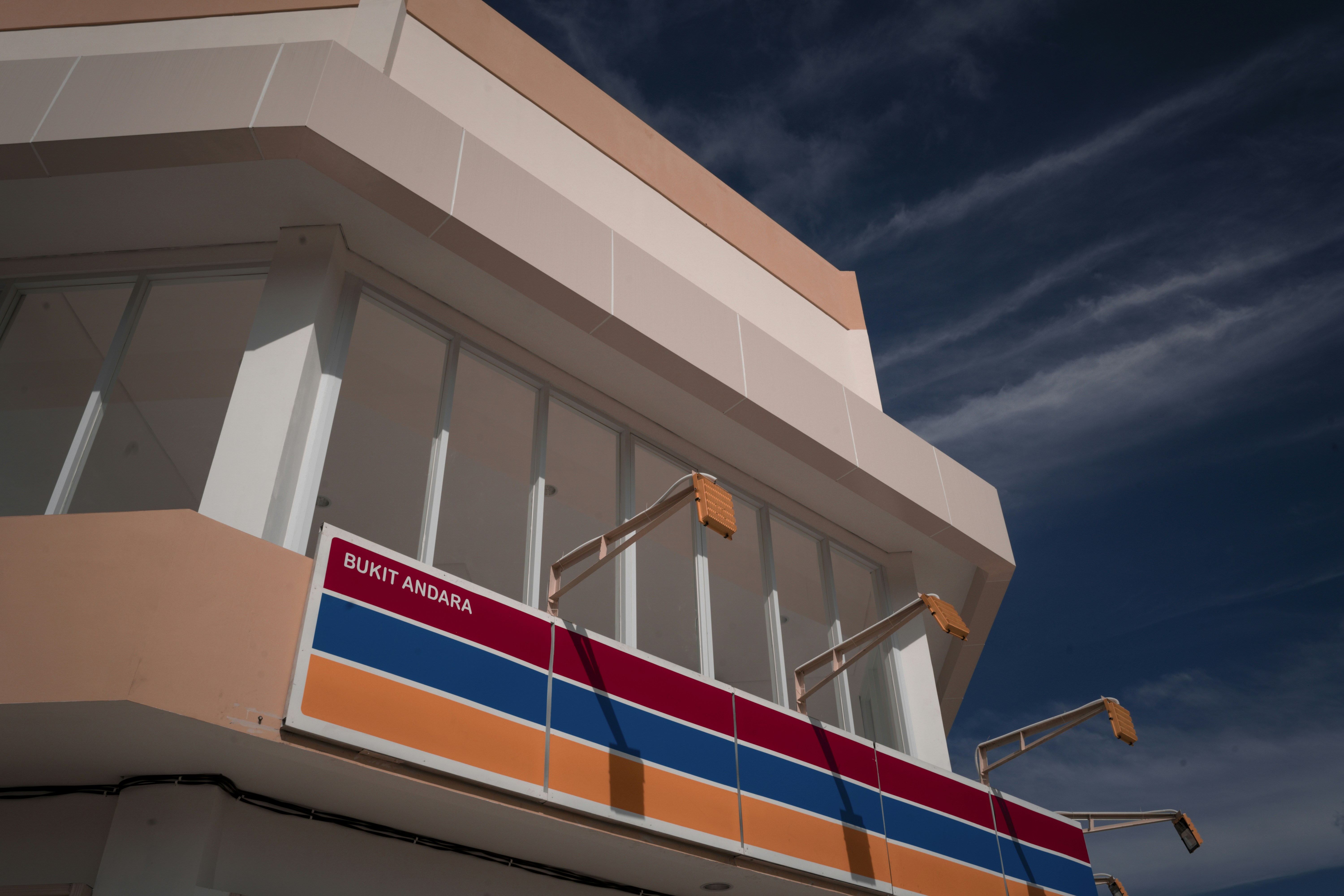 Contemporary building facade with geometric shapes and bold colors against a deep blue sky.