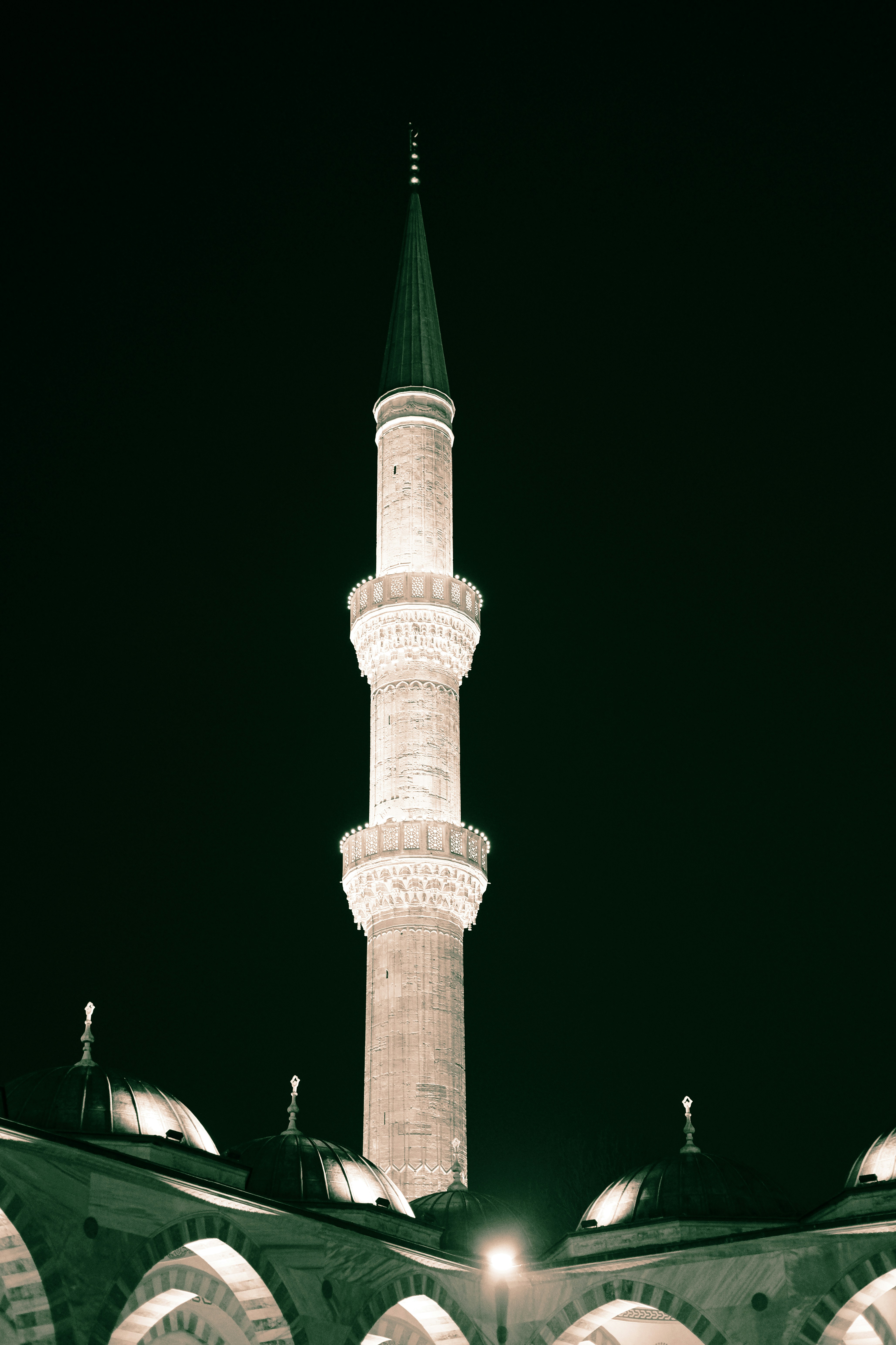 Illuminated Needle: A Nighttime Minaret Framed by Arched Domes