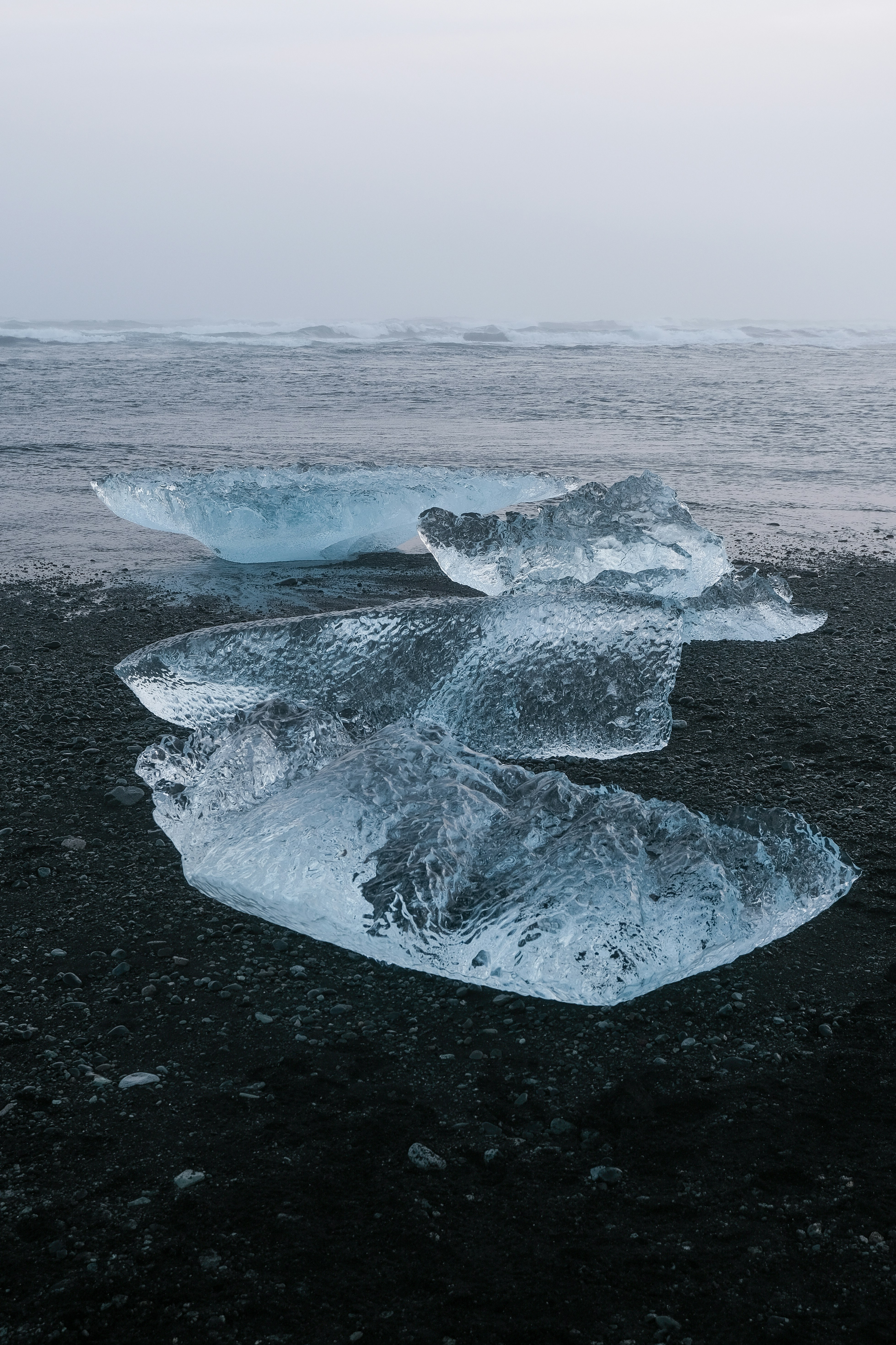 Chiseled Ice Fragments on a Pebble Beach at Dusk