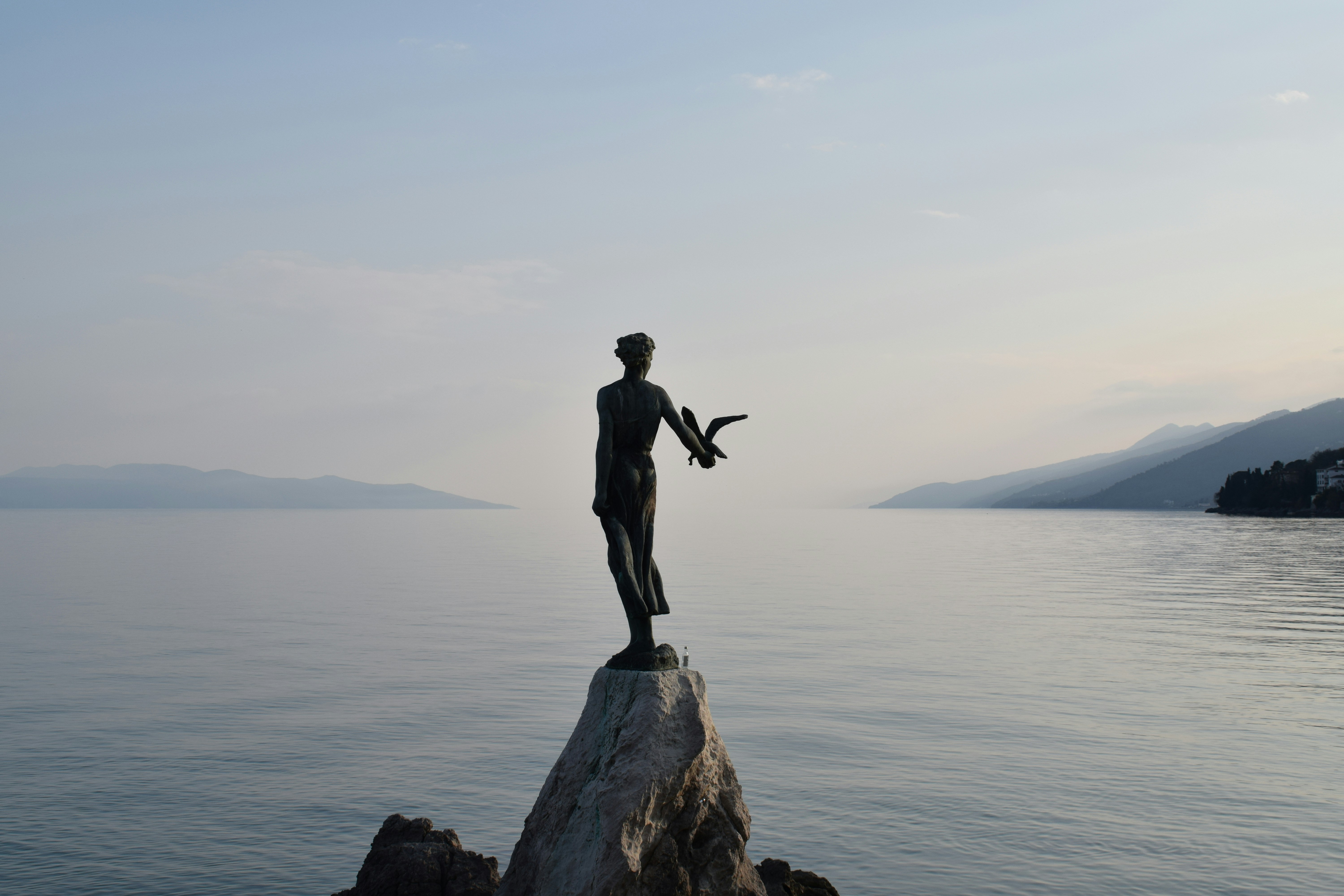 Lone Bronze Figure on a Sea-Swept Crag
