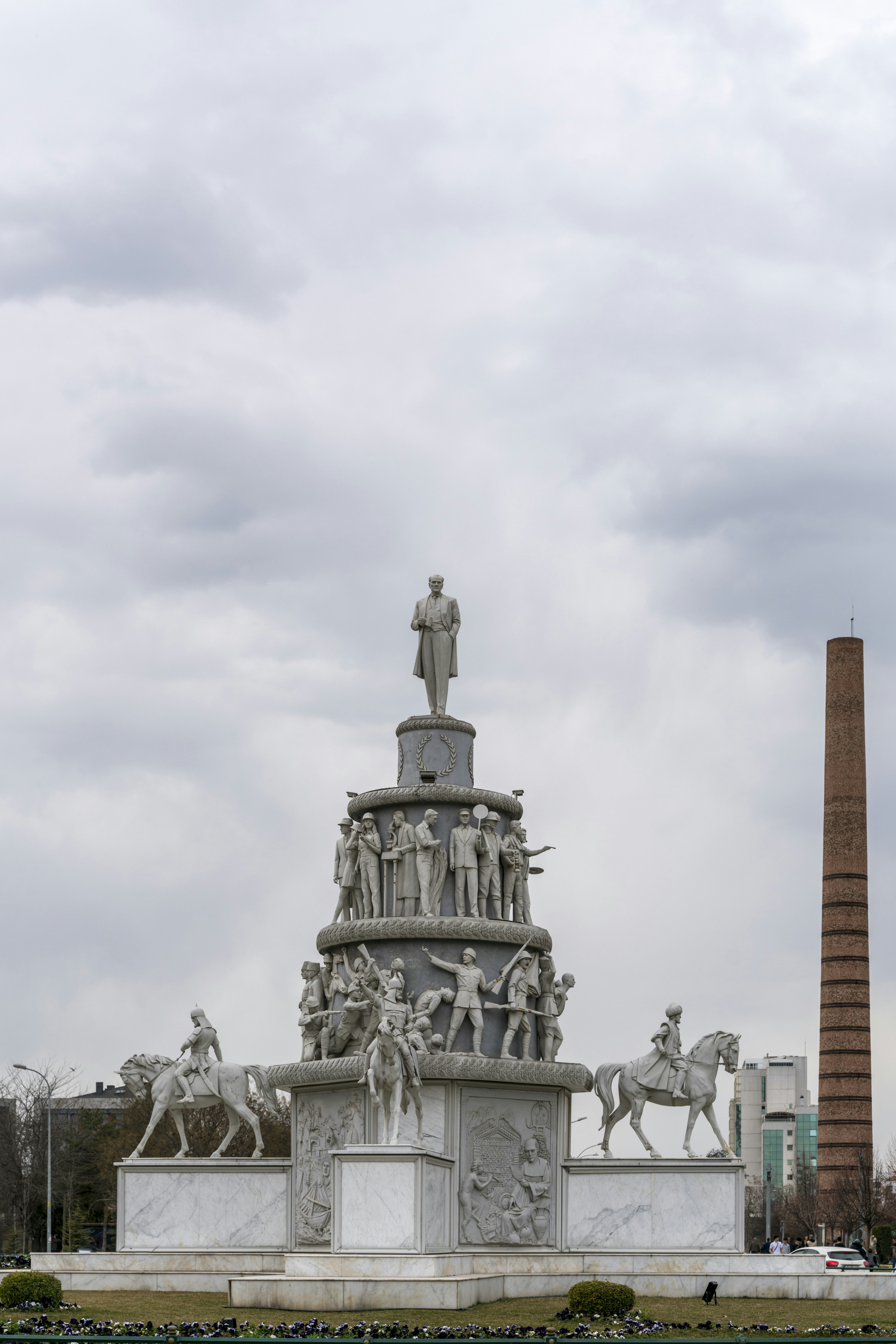 Tiered Marble Sentinel: Central Statue Surrounded by Figures in an Urban Square
