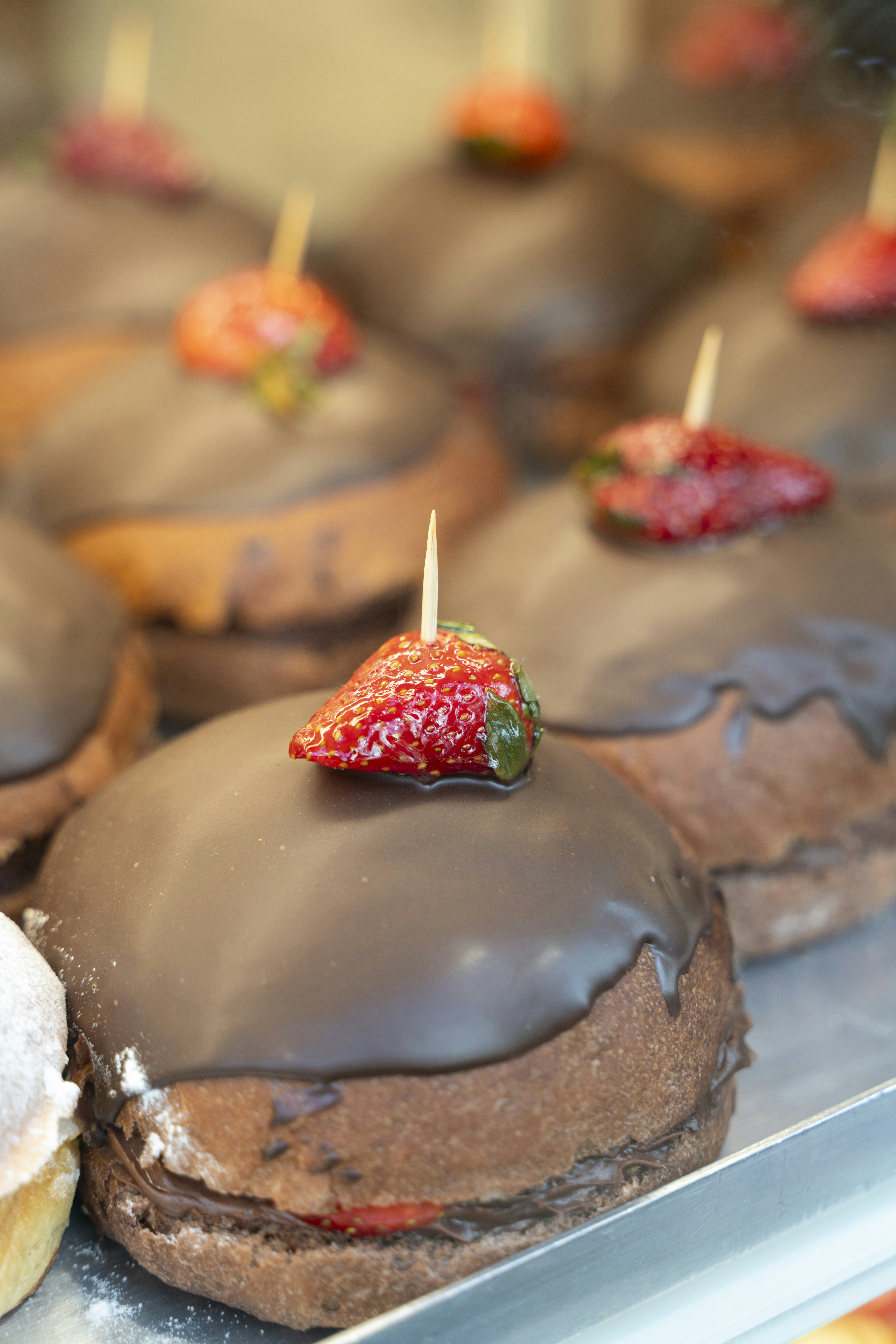 Strawberry Crowned Chocolate Mini-Donuts in a Bakery Display