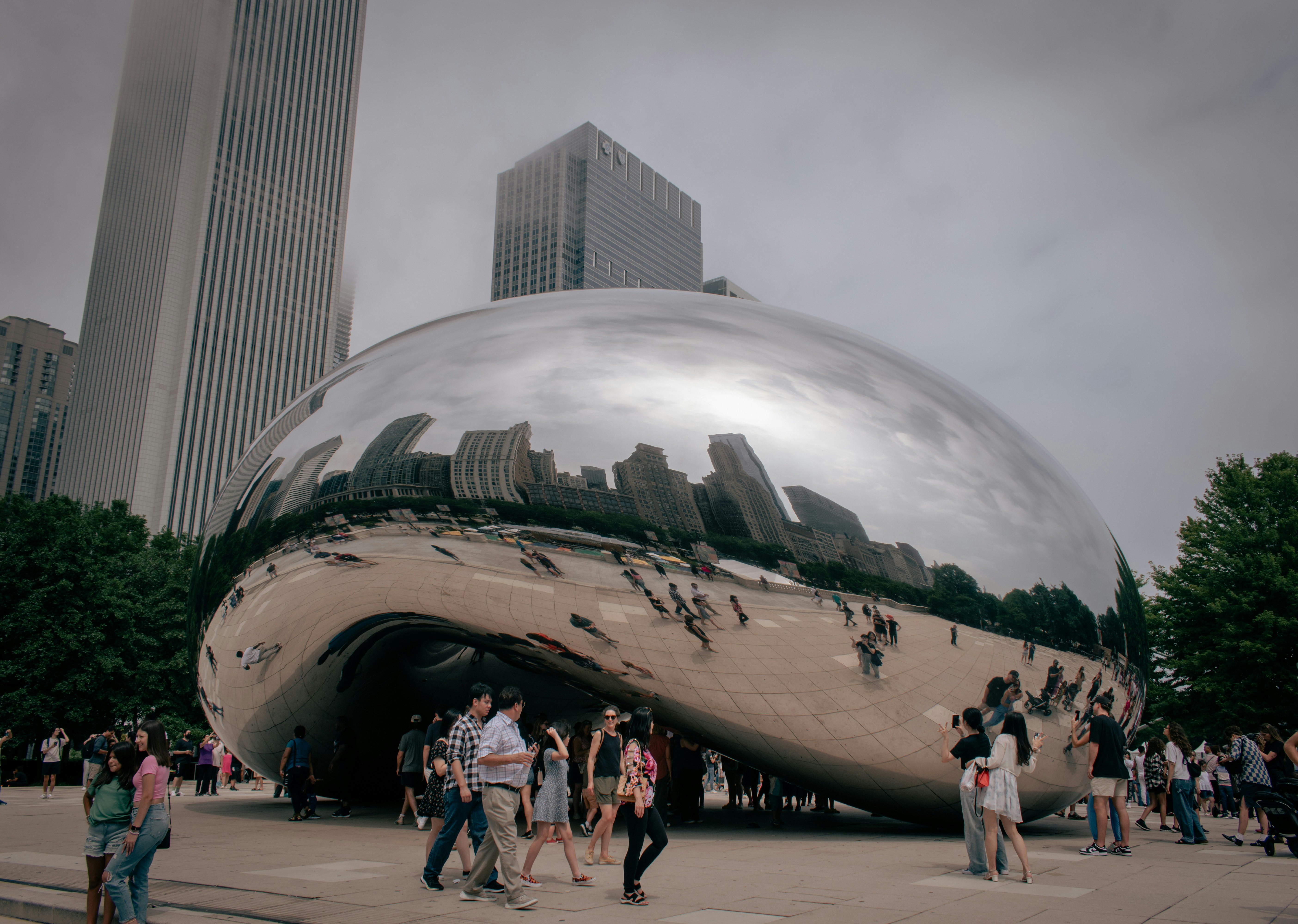 A group of people standing in front of a large shiny object photo ...
