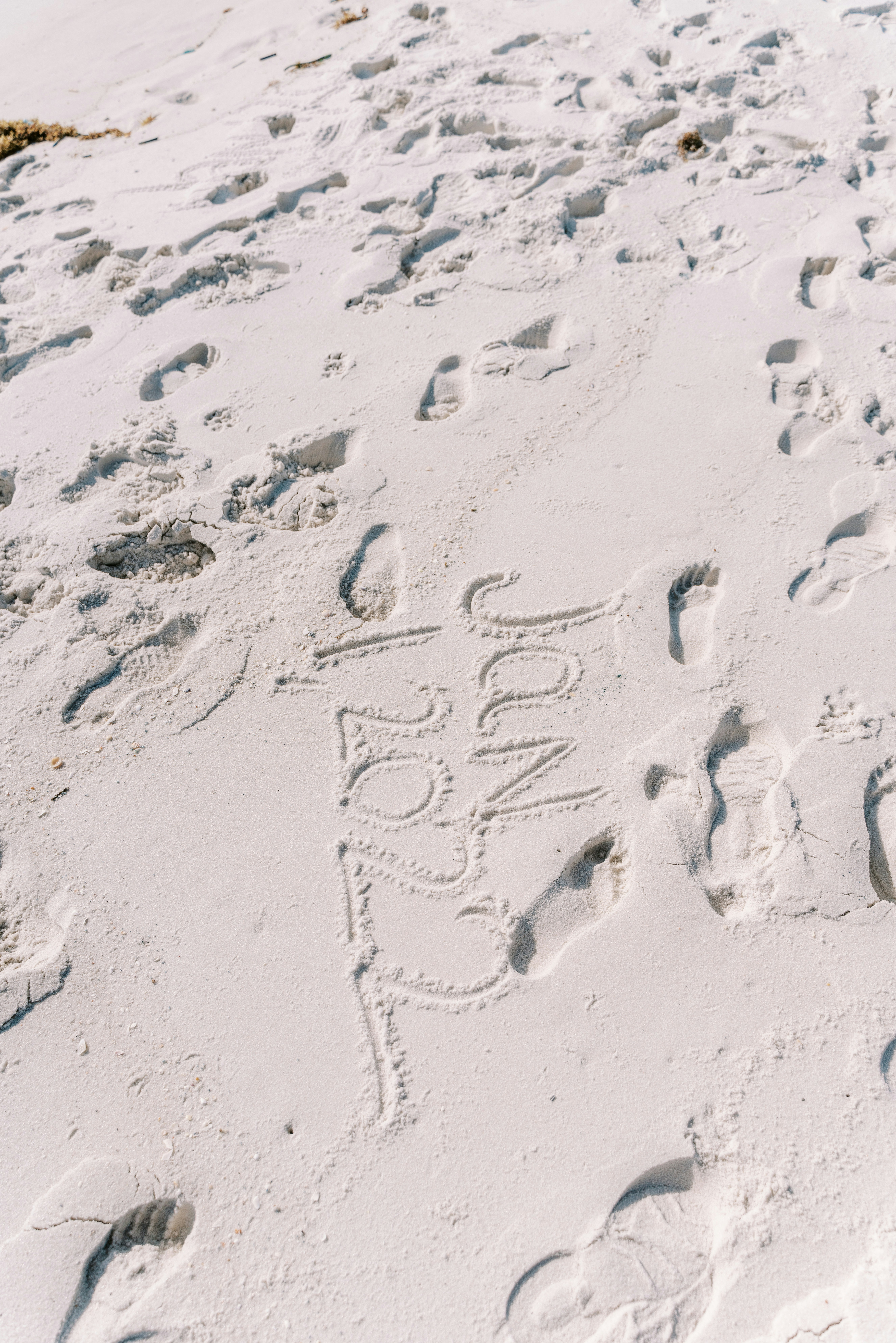 A sandy beach covered in footprints and writing photo – Free Symbol ...
