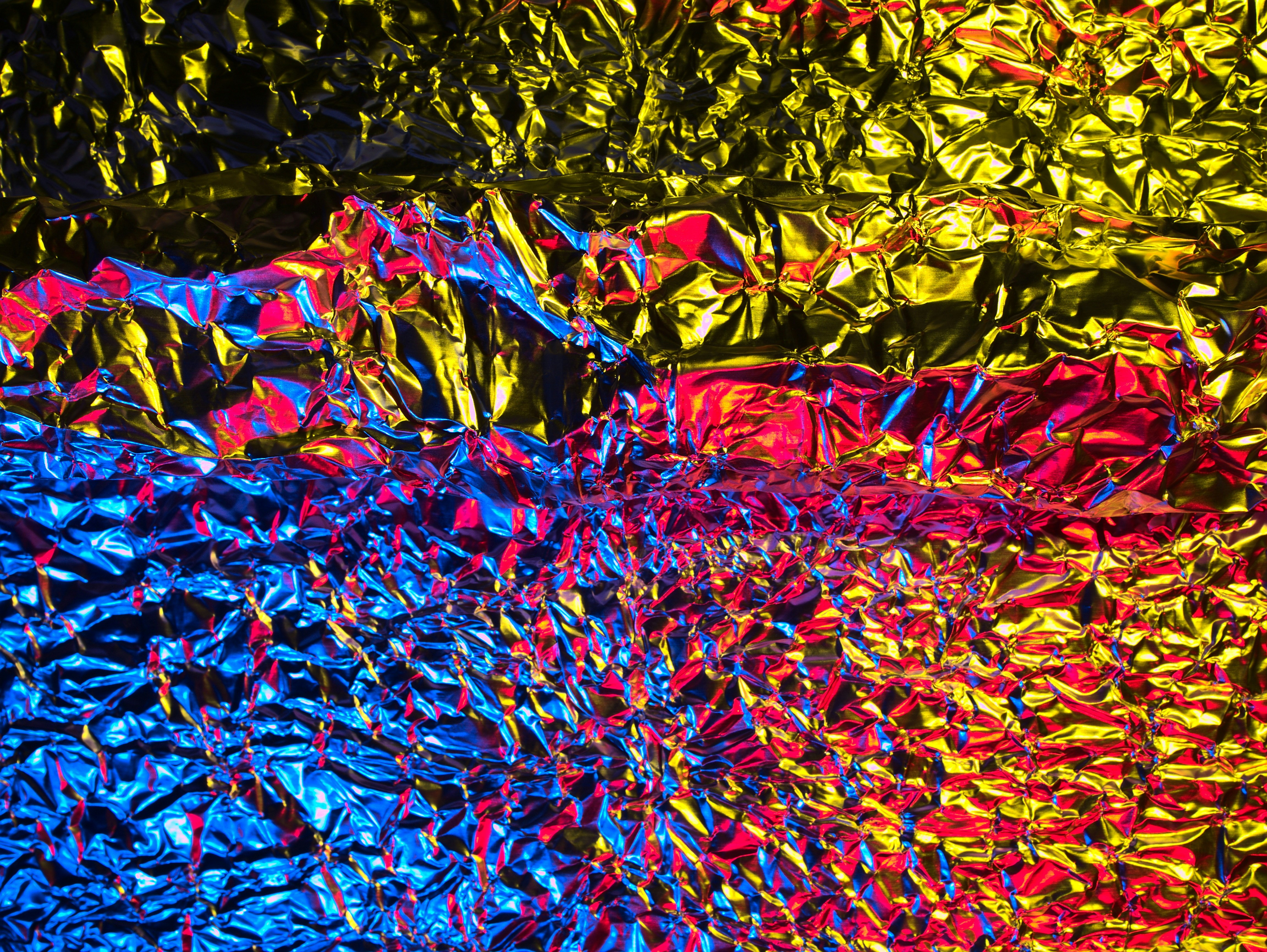 Vibrant crumpled foil reflecting a spectrum of blue, red, and yellow hues.