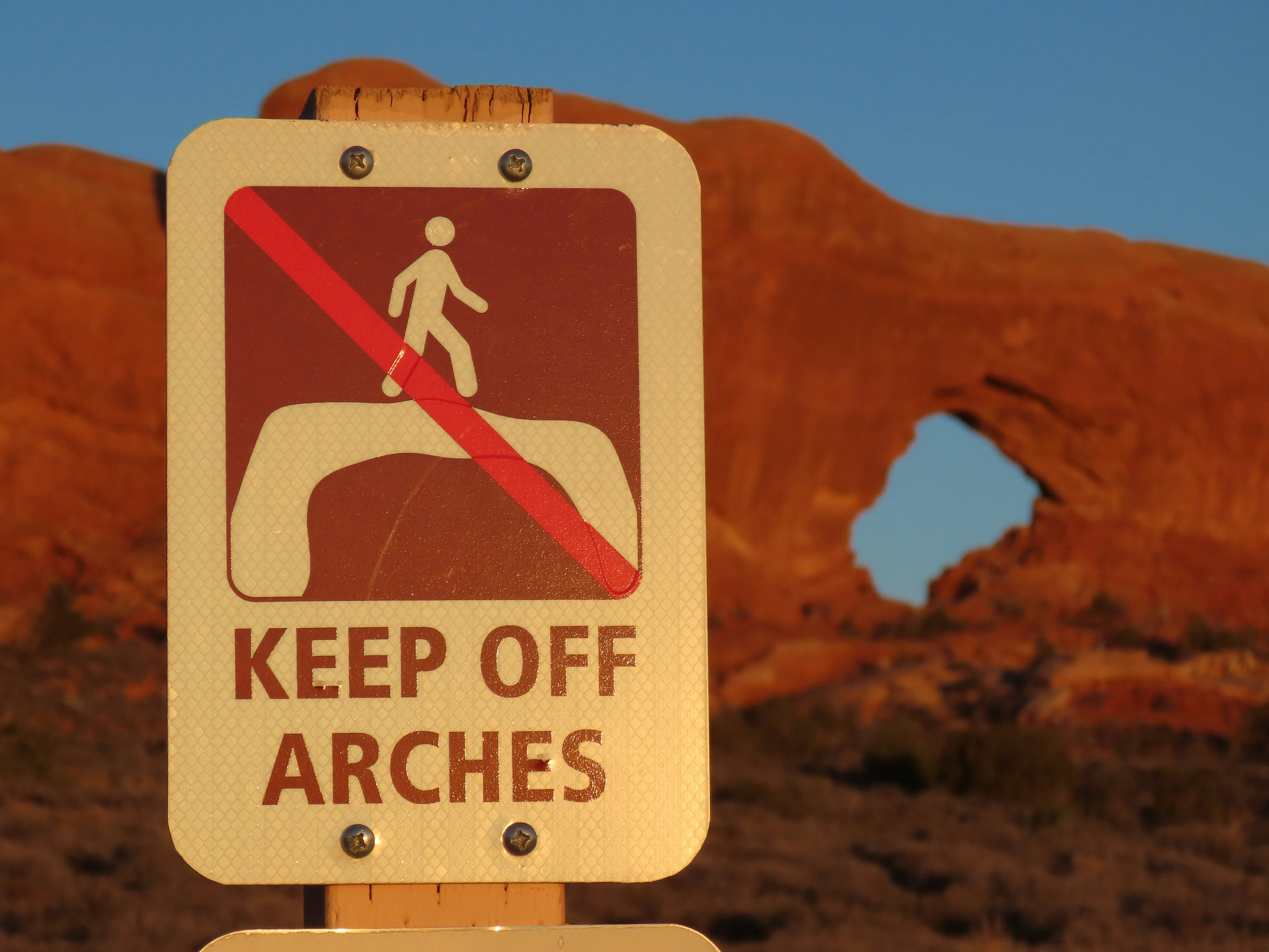 Red-Rock Sentinel: The 'Keep Off Arches' Sign Before a Desert Natural Arch