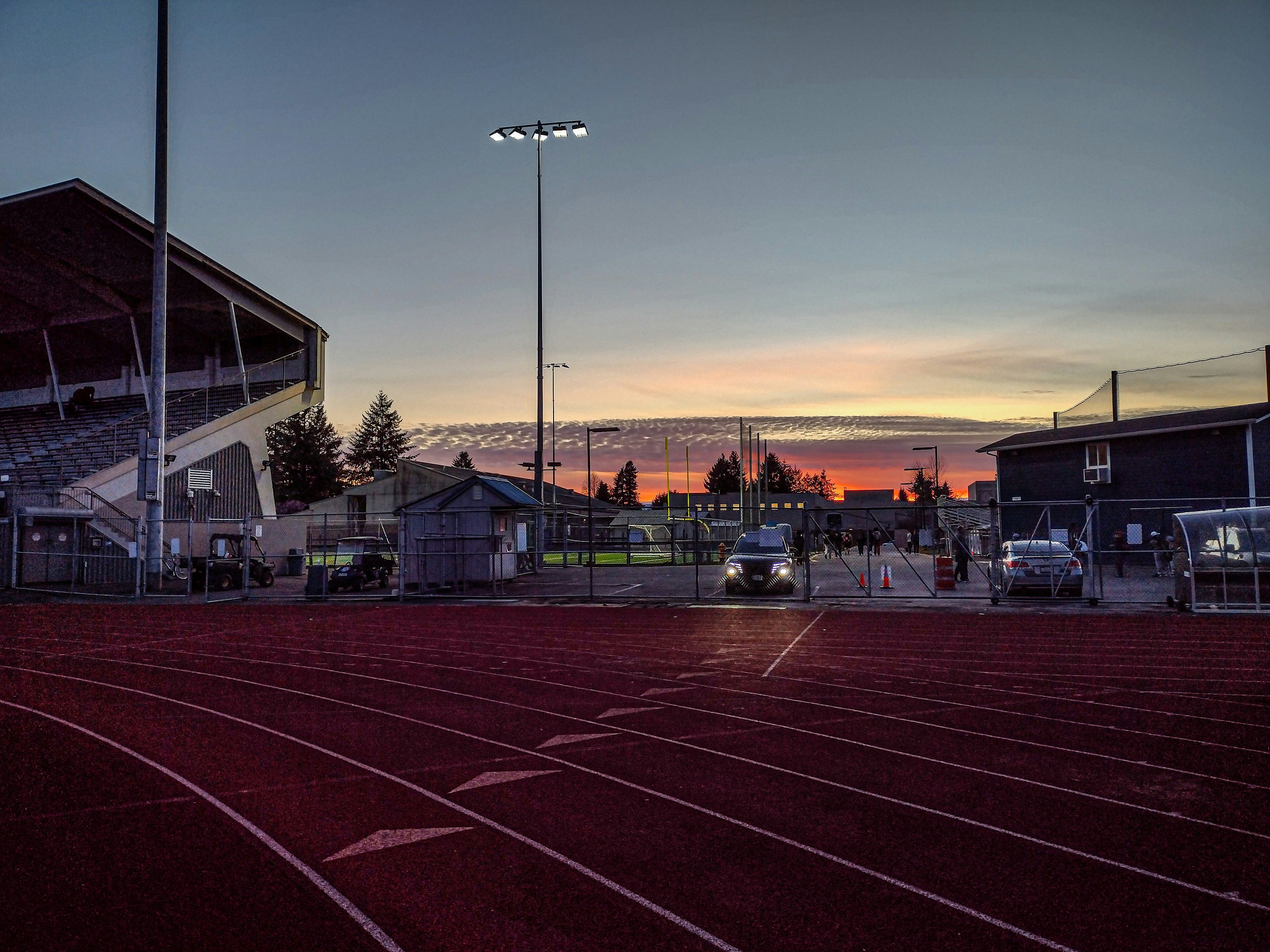 The sun is setting over a track in a stadium photo – Free Sunset Image ...
