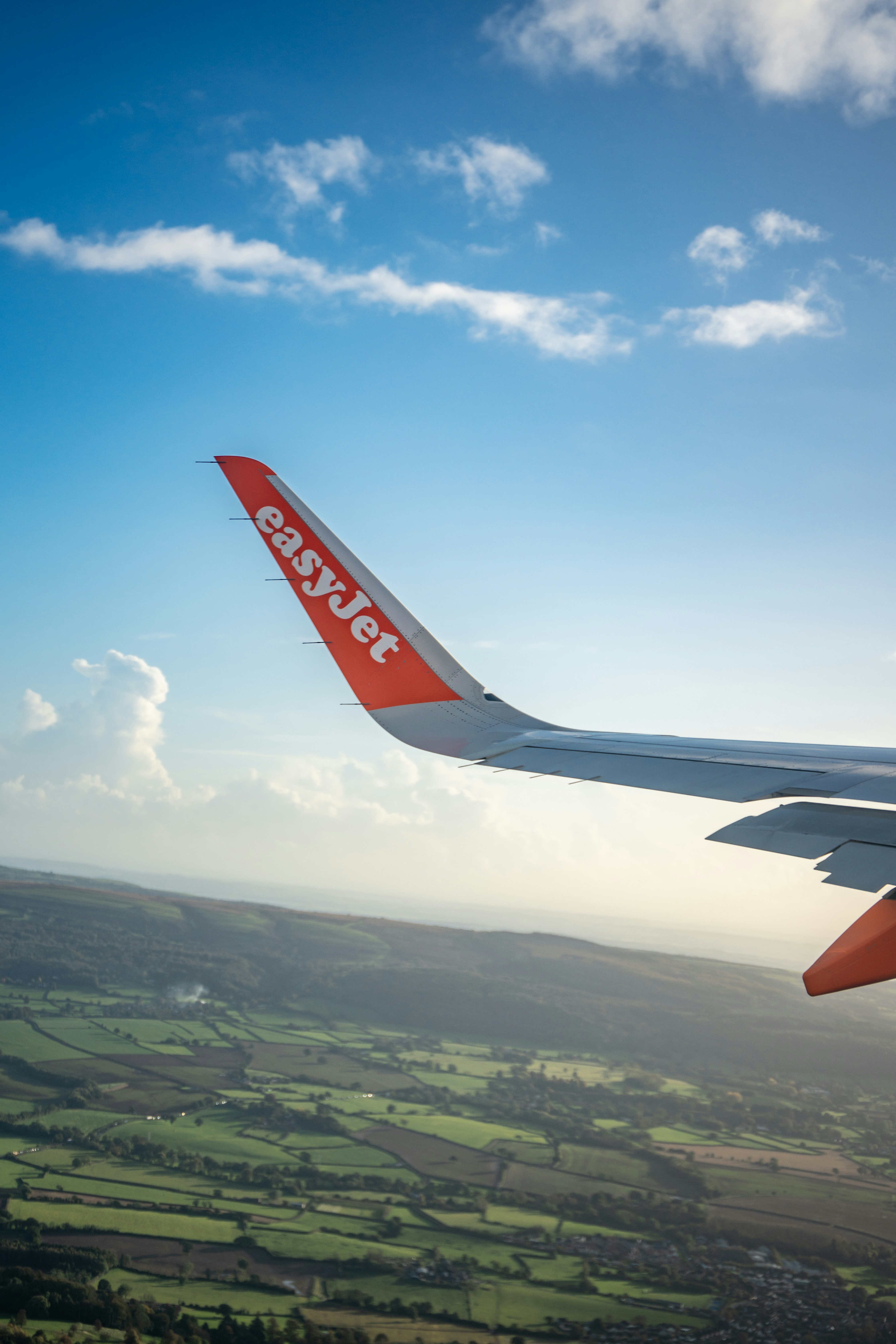Winglet in the Blue: EasyJet's Red Swoop Over a Patchwork Landscape