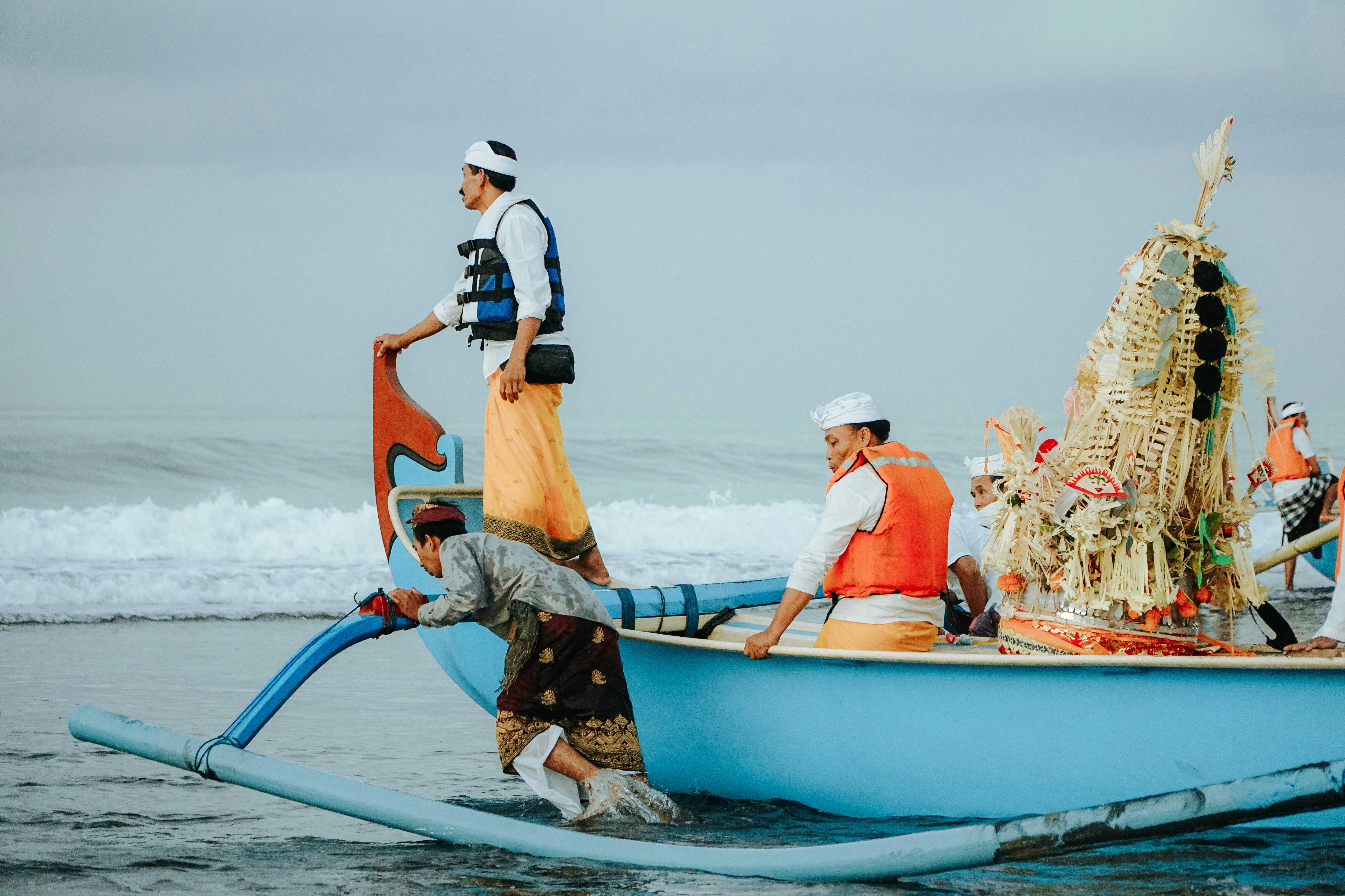 Blue Outrigger at Sea: Ceremonial Craft Gliding Past Calm Waters