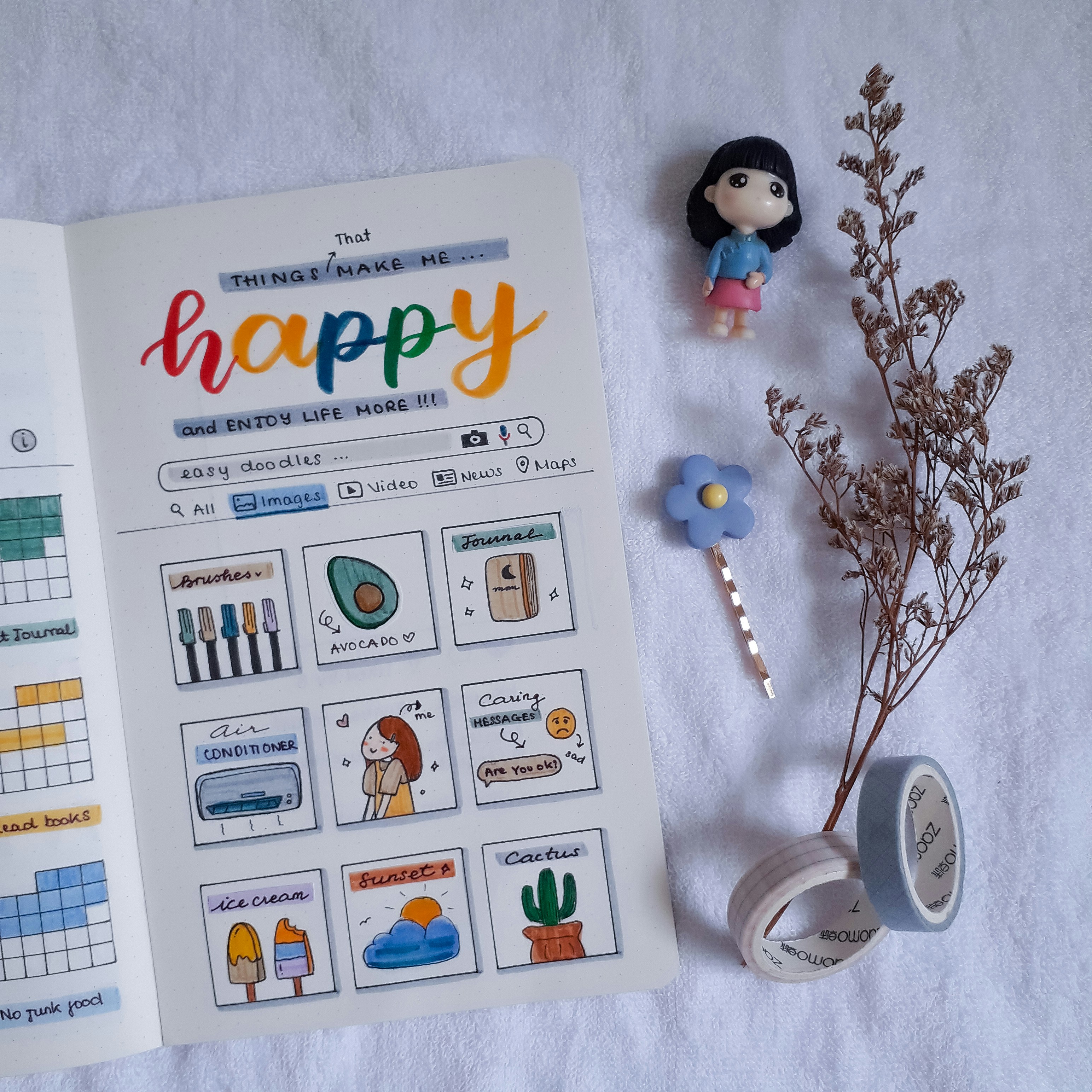 Colorful journal spread celebrating happiness with doodles, a figurine, and dried flowers arranged artfully on a soft background.