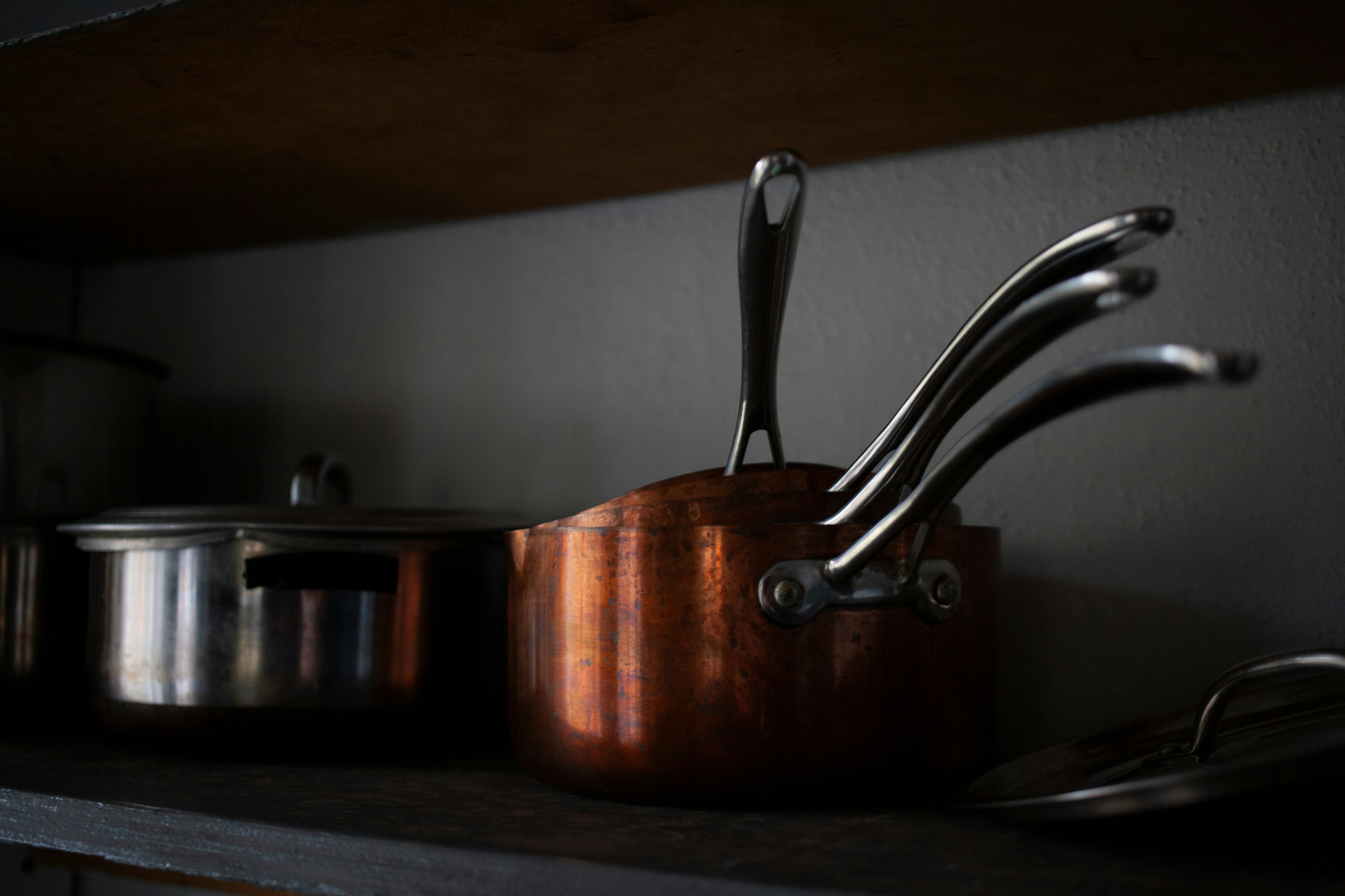 Copper Pot Symphony on a Dim Kitchen Shelf