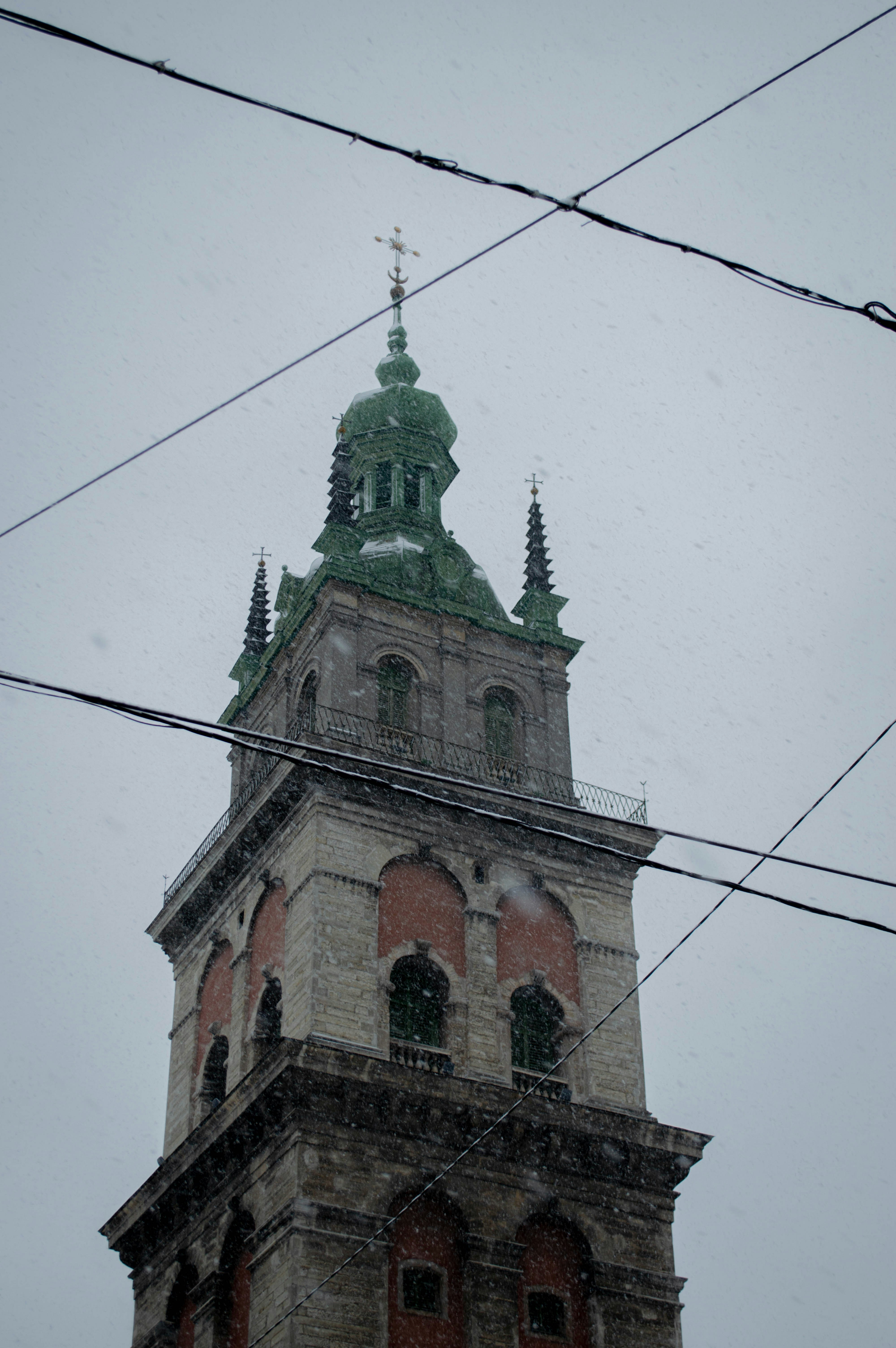Verdant Spire in Snow: The Green-Topped Tower Amid Winter Wires