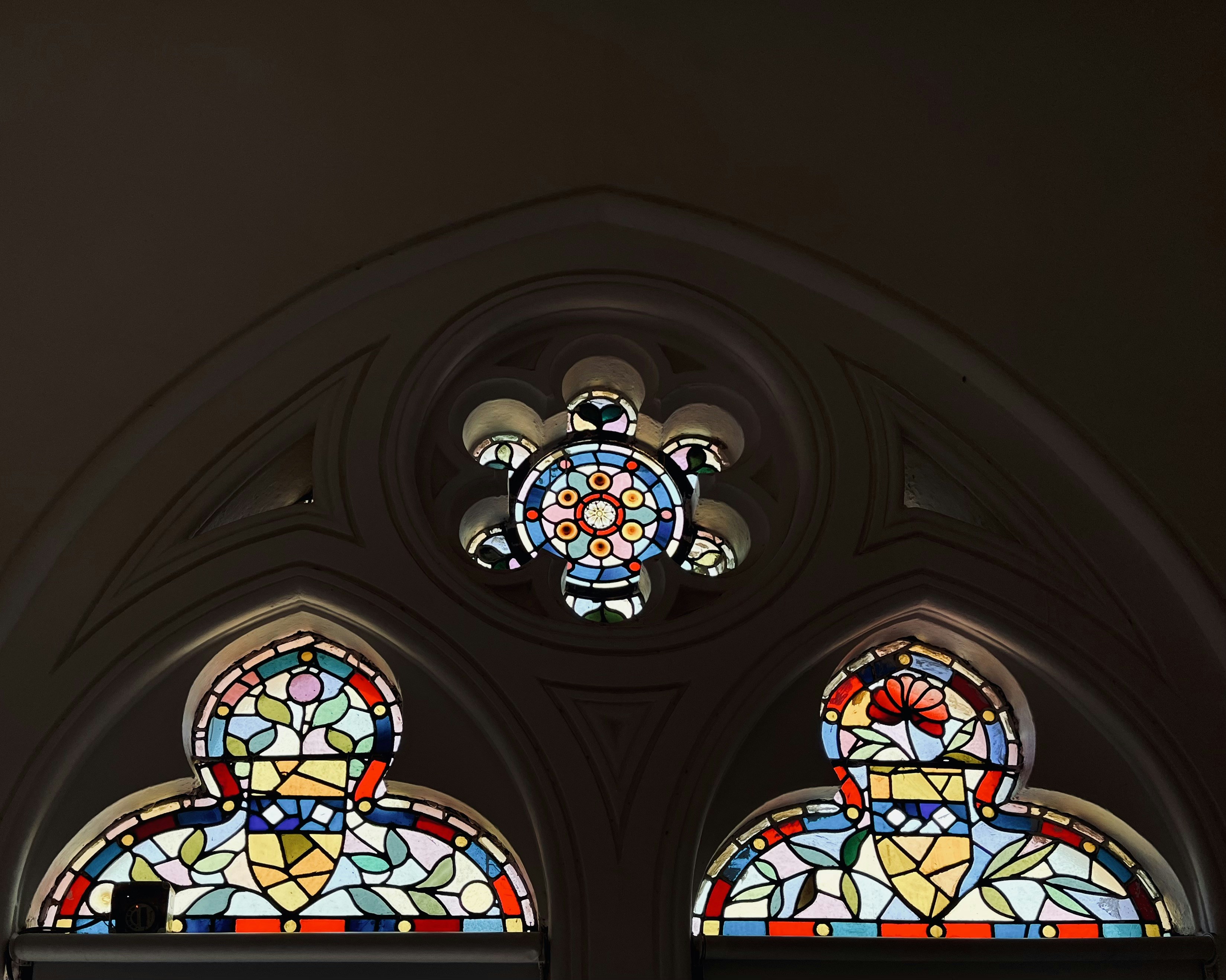 Intricate stained glass windows in a dimly lit church interior.