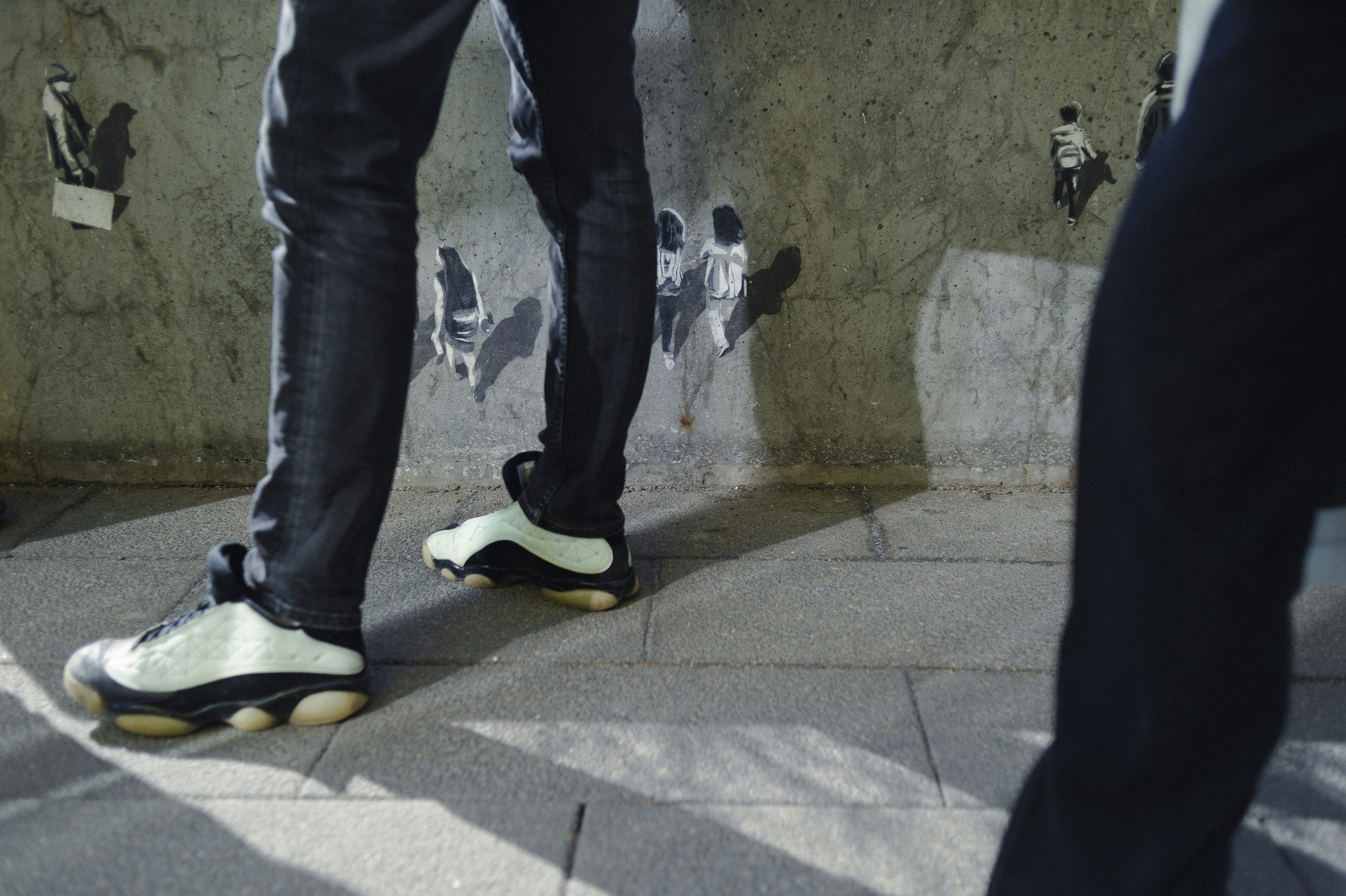 Stride Through Graffitied Pavement: White Sneakers in Motion