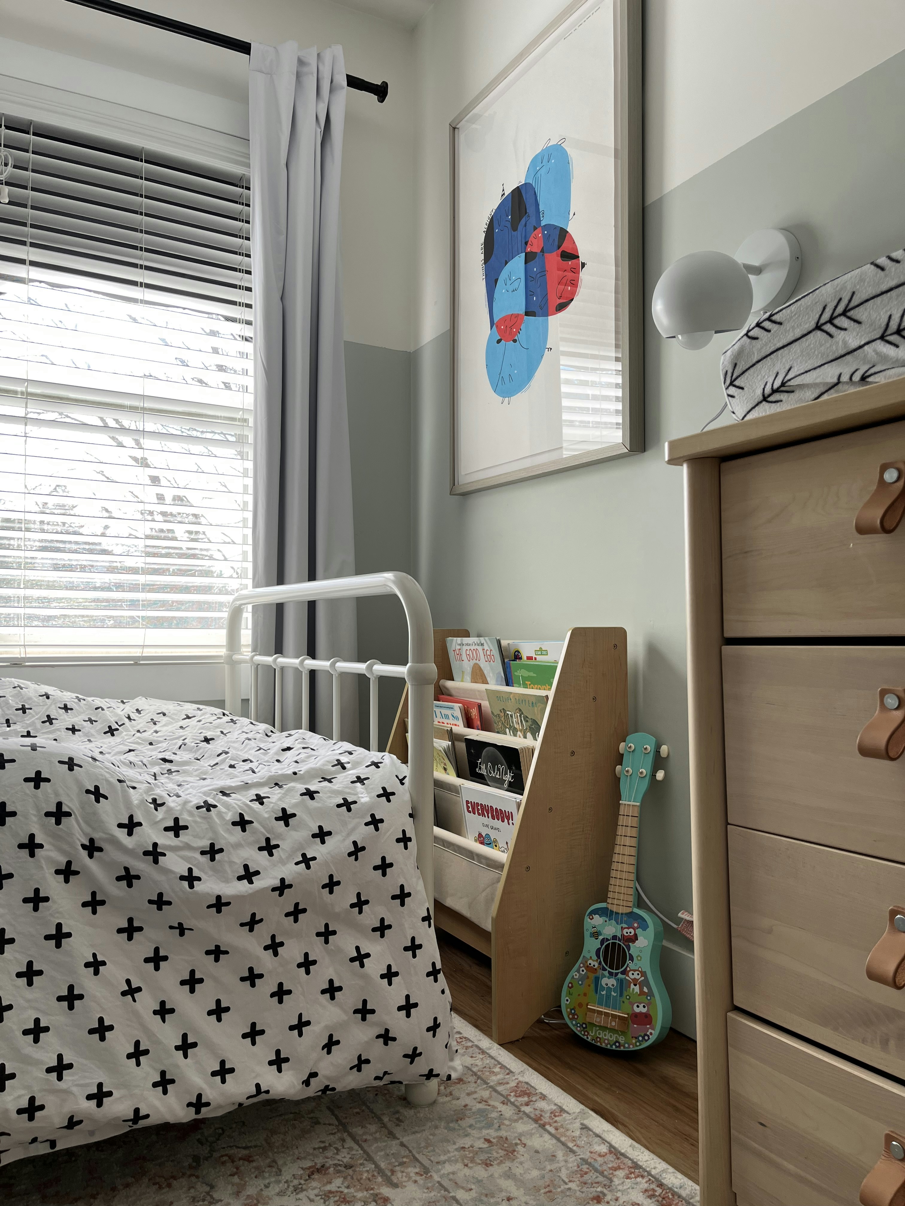 Brightly decorated children's bedroom featuring a bed with patterned bedding, a colorful guitar, and a whimsical wall art piece.