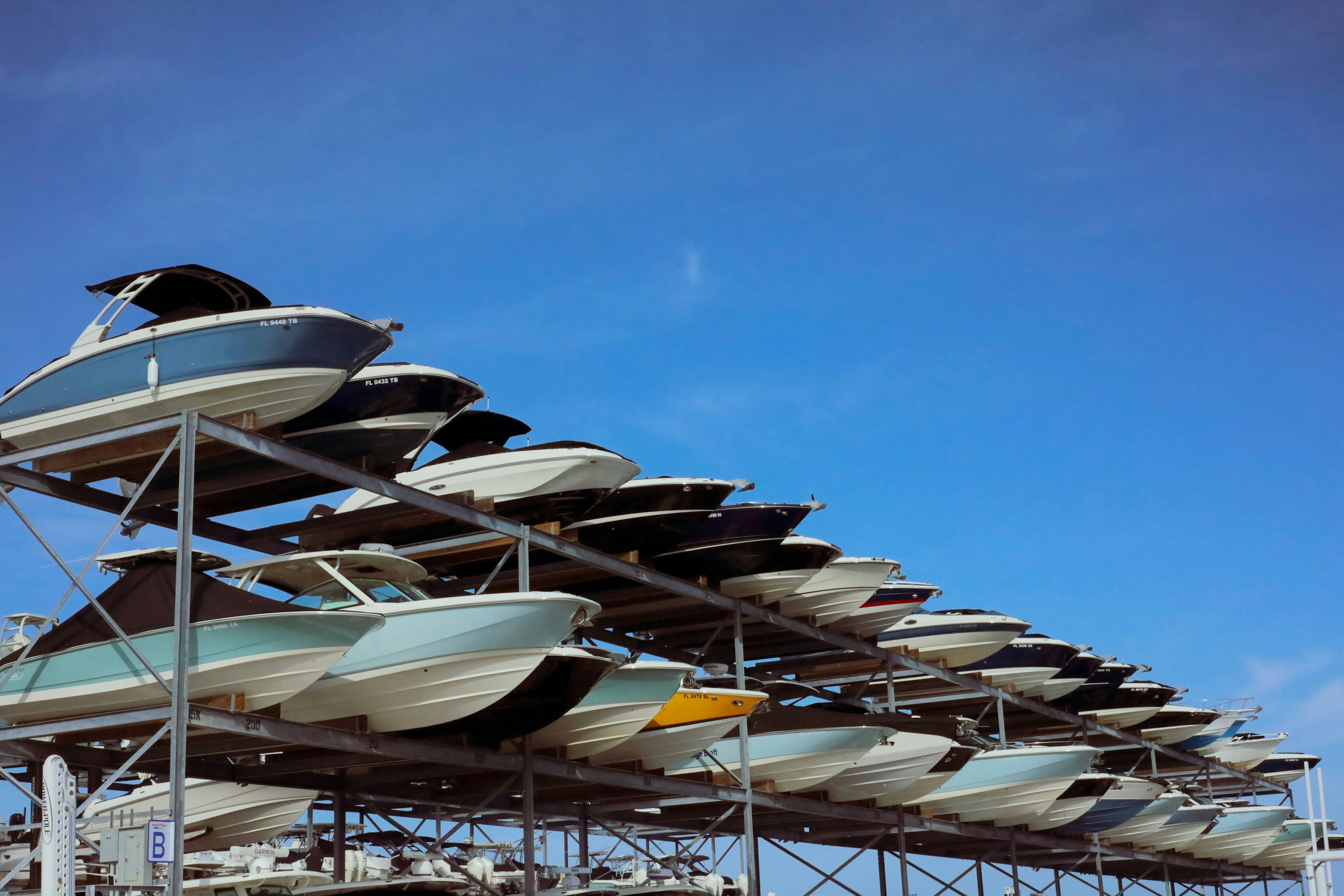Boats neatly stacked on a metal rack under a clear blue sky.