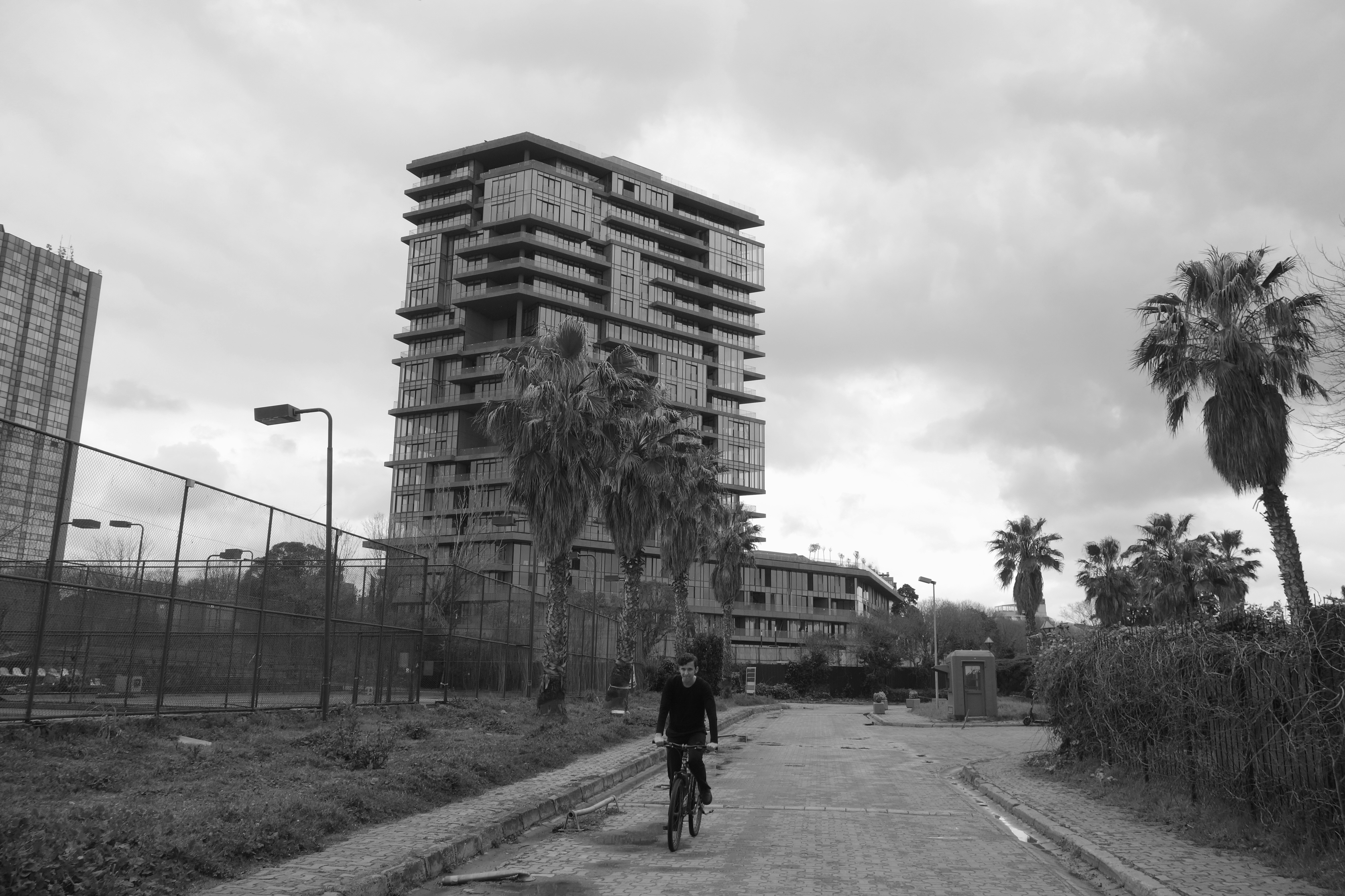 Cyclist on a Winding Path Beneath a Stacked Modern Building