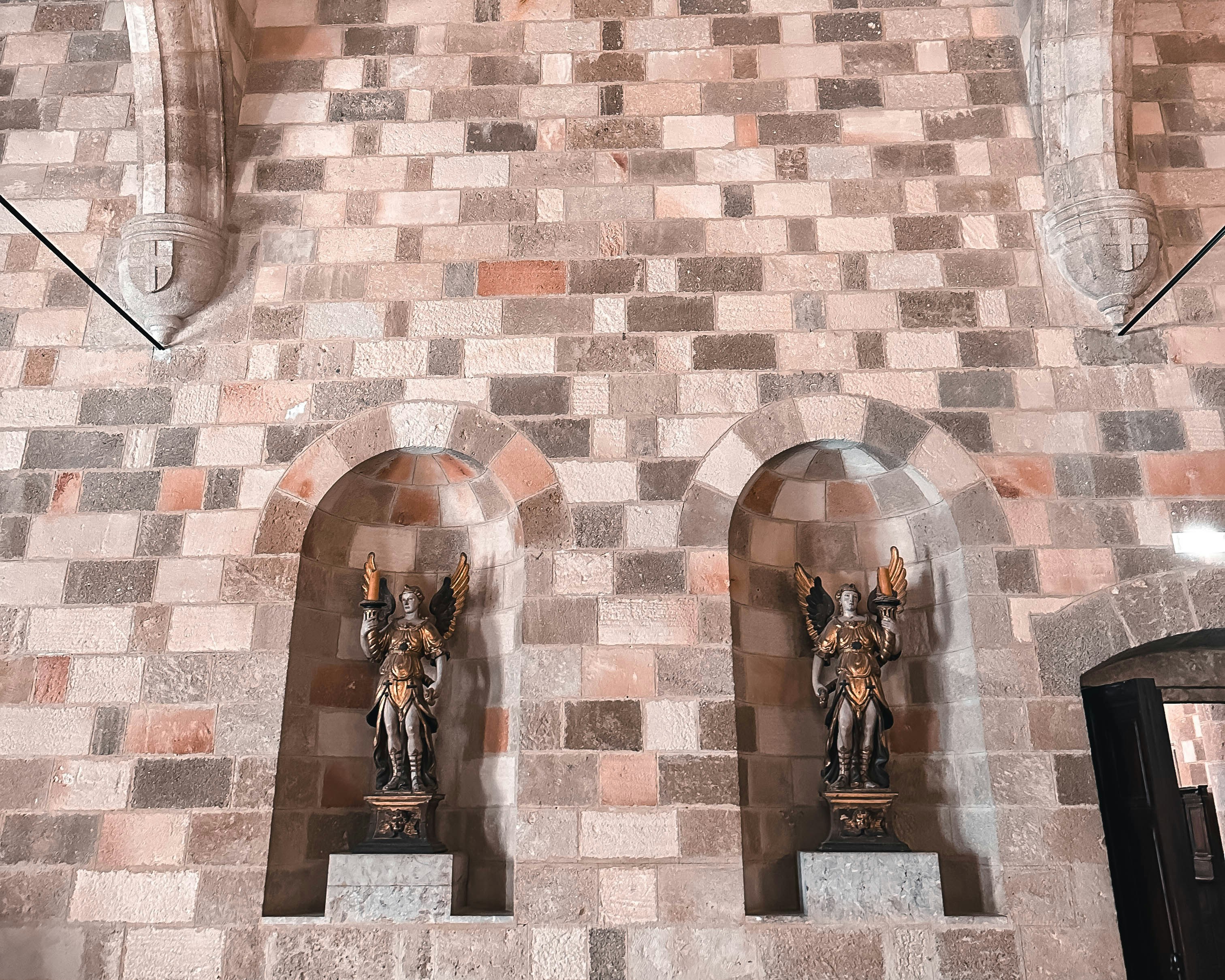 Twin Stone Guardians Adorn Arched Niches in a Checkered Brick Wall