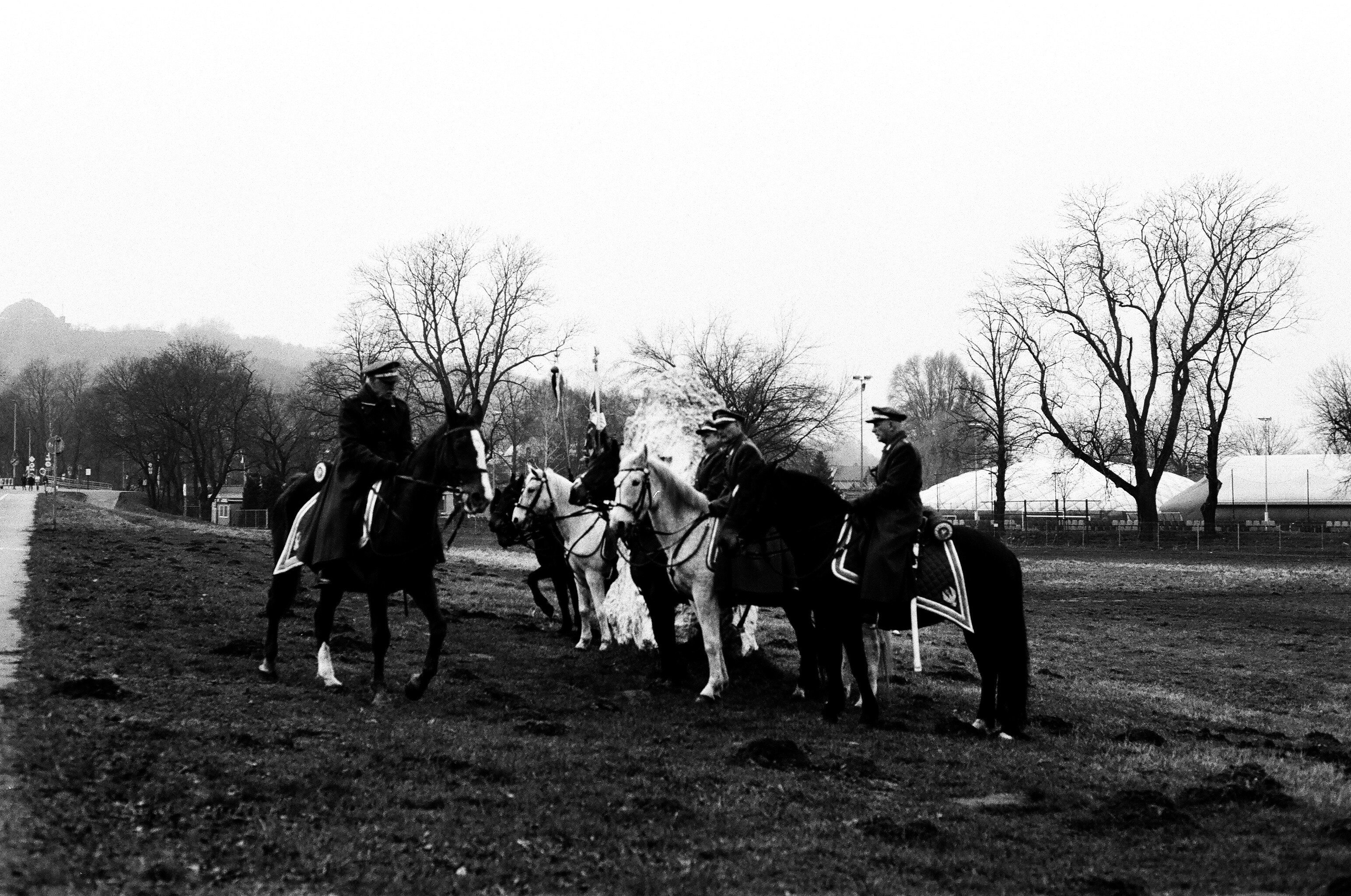 Black-and-white photograph of a group of cavalry on horseback gathered in a muddy field with bare trees in the background.