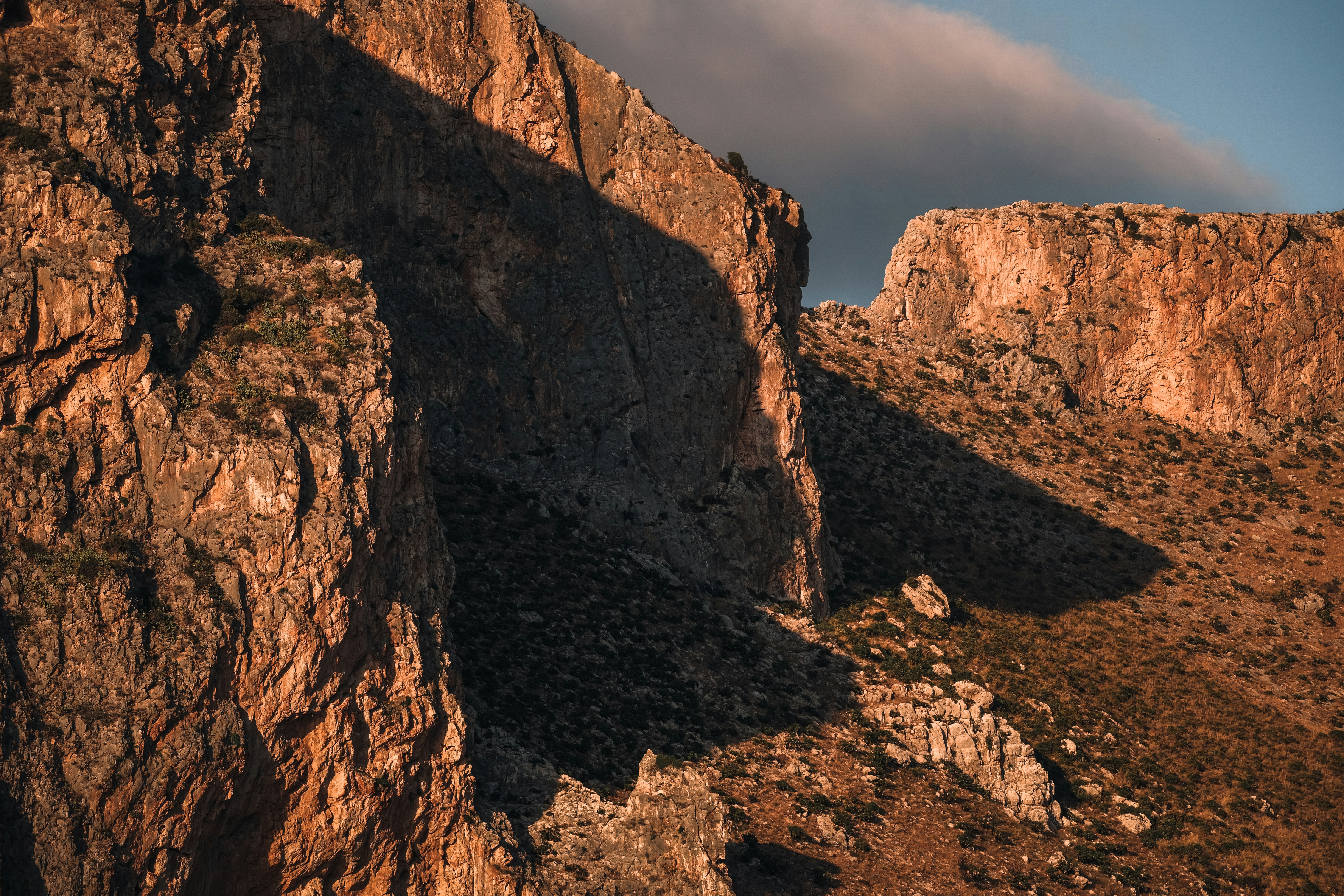 A rocky cliff with a small patch of grass growing on the side of it ...