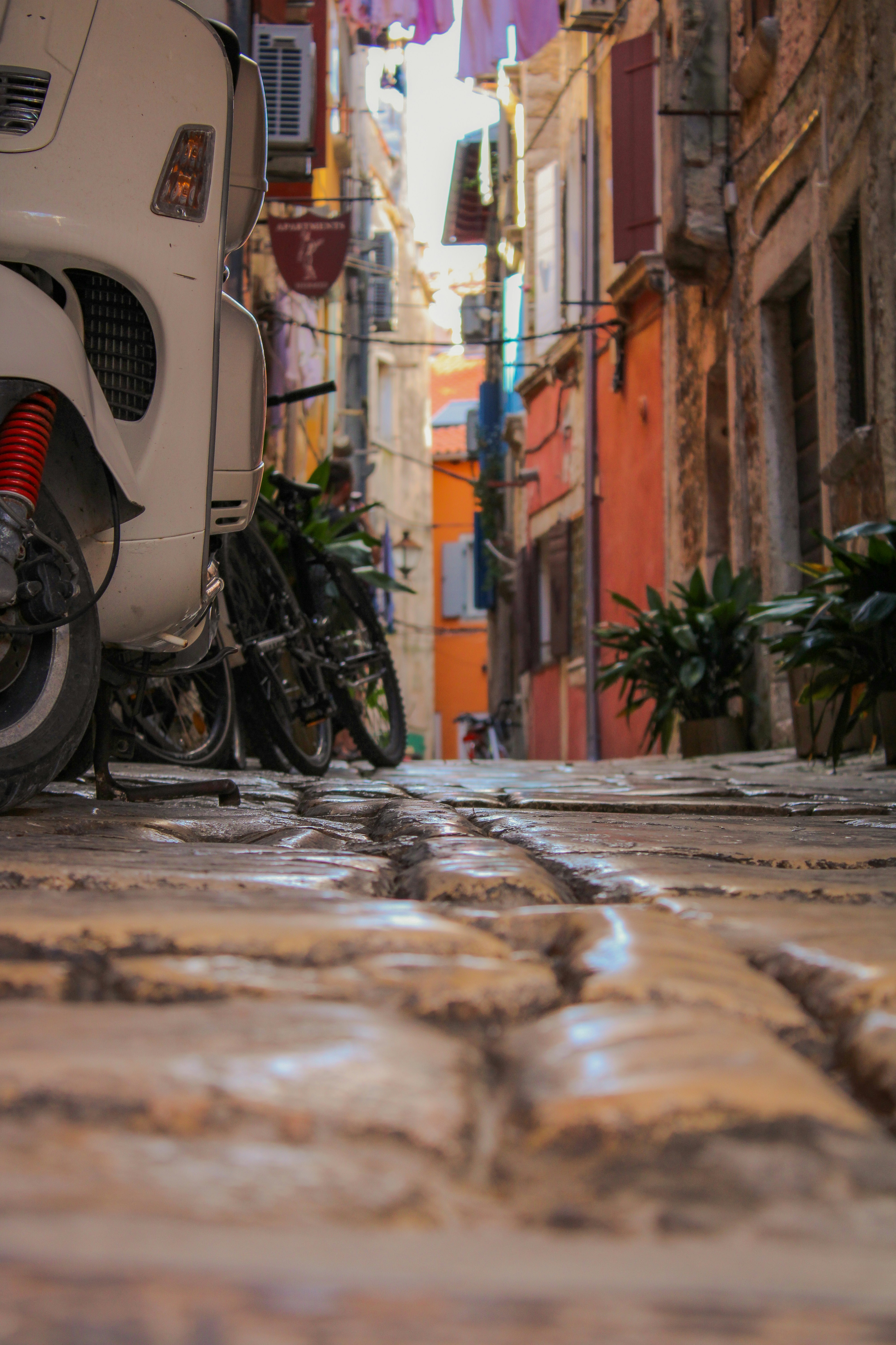 Sunlit Calle: A Scooter Anchoring a Vibrant Alley of Colorful Facades