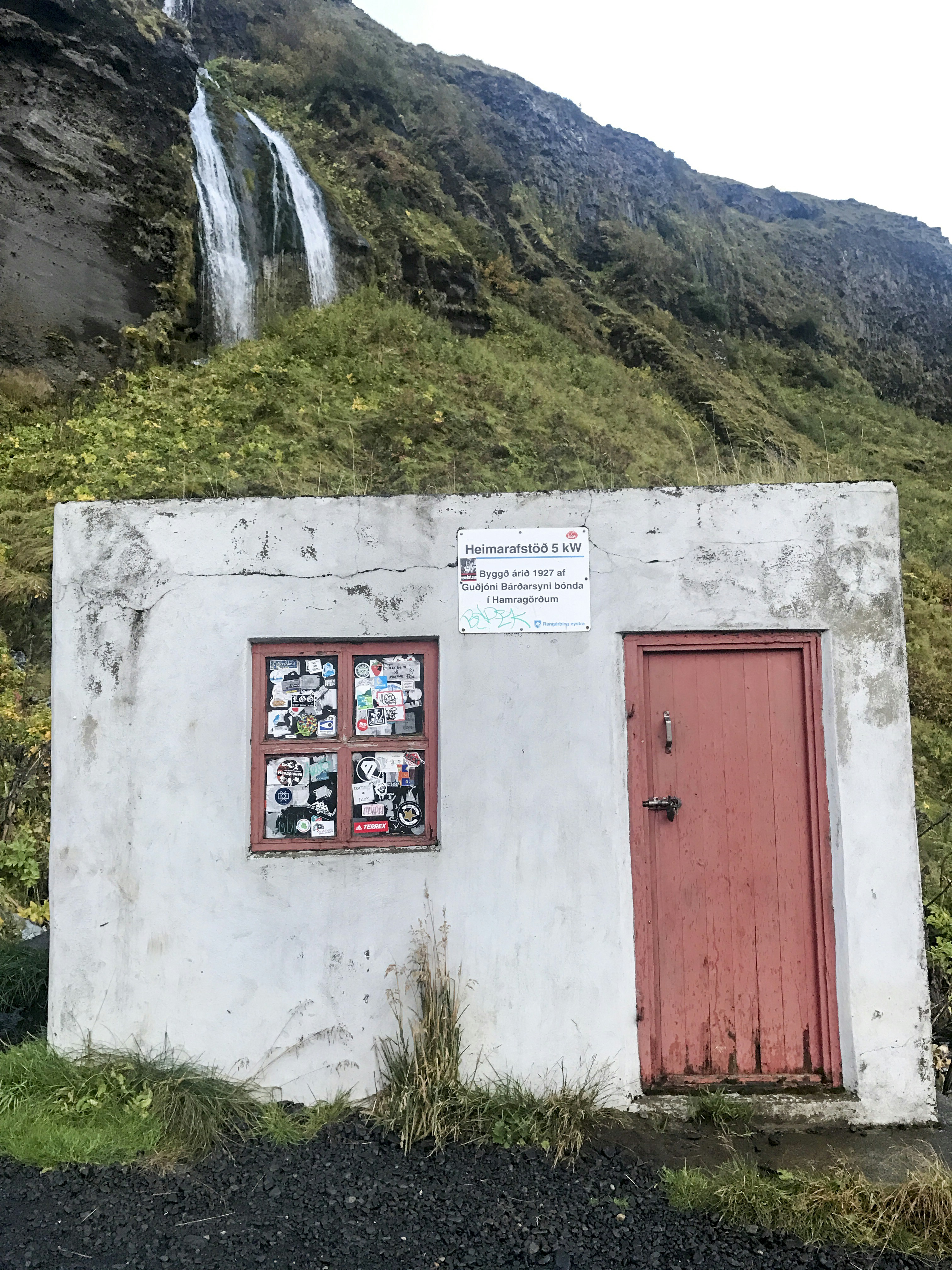 Red Door Refuge Beneath a Cascading Mountain Waterfall