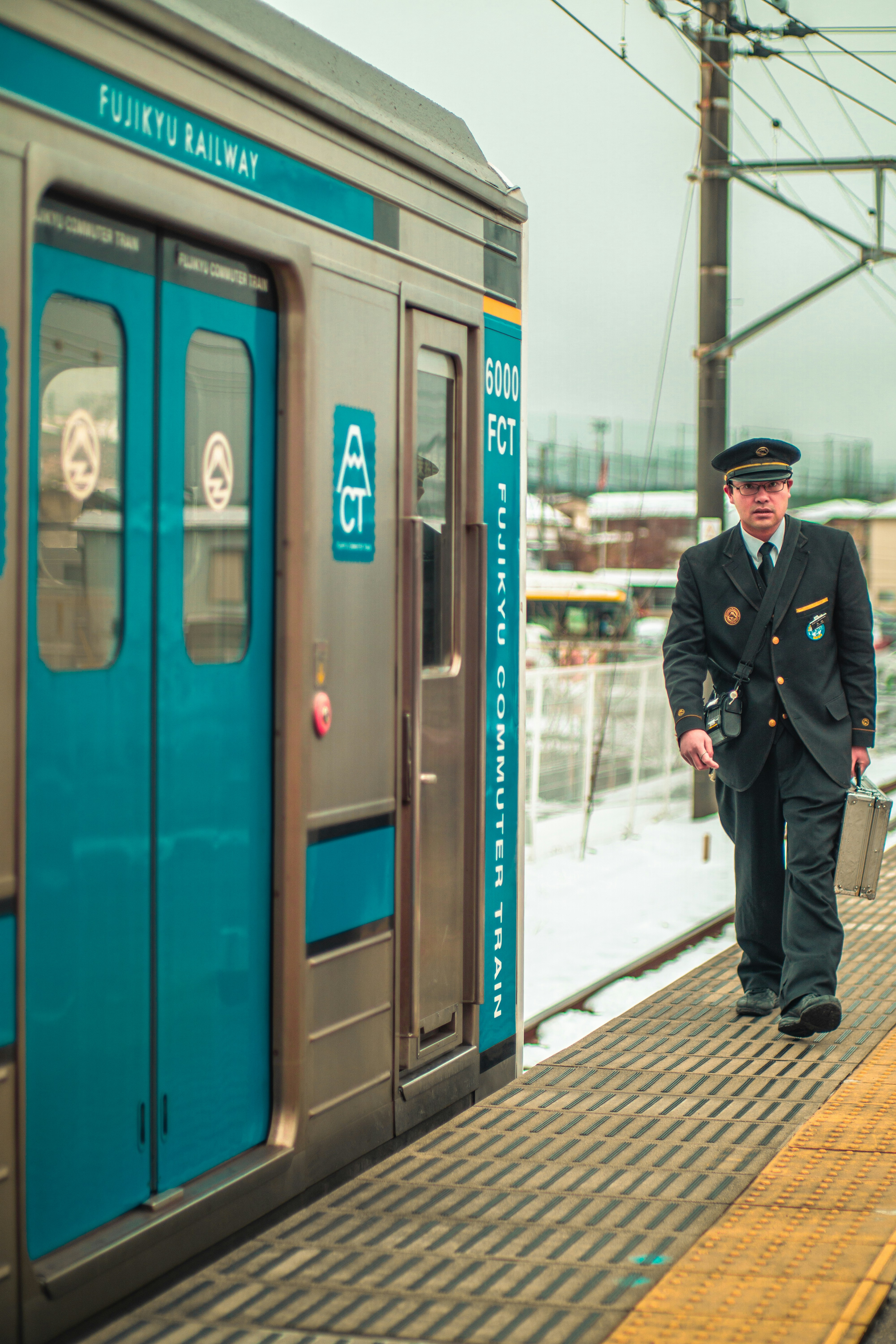 A man in a uniform walking next to a train photo – Free Fuji Image on ...