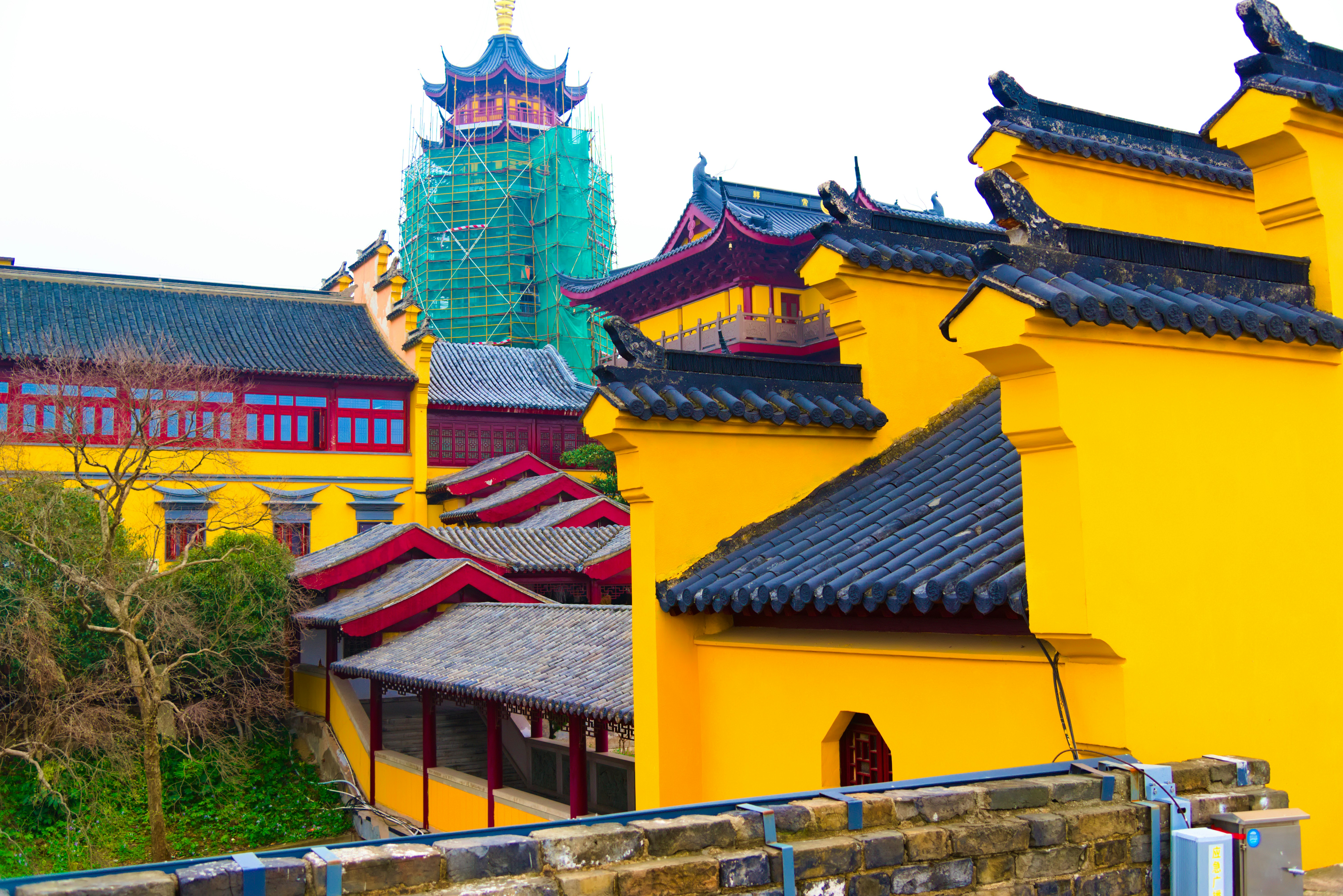 Scaffolding-Clad Spire Rising Behind Sunlit Yellow Temple Walls