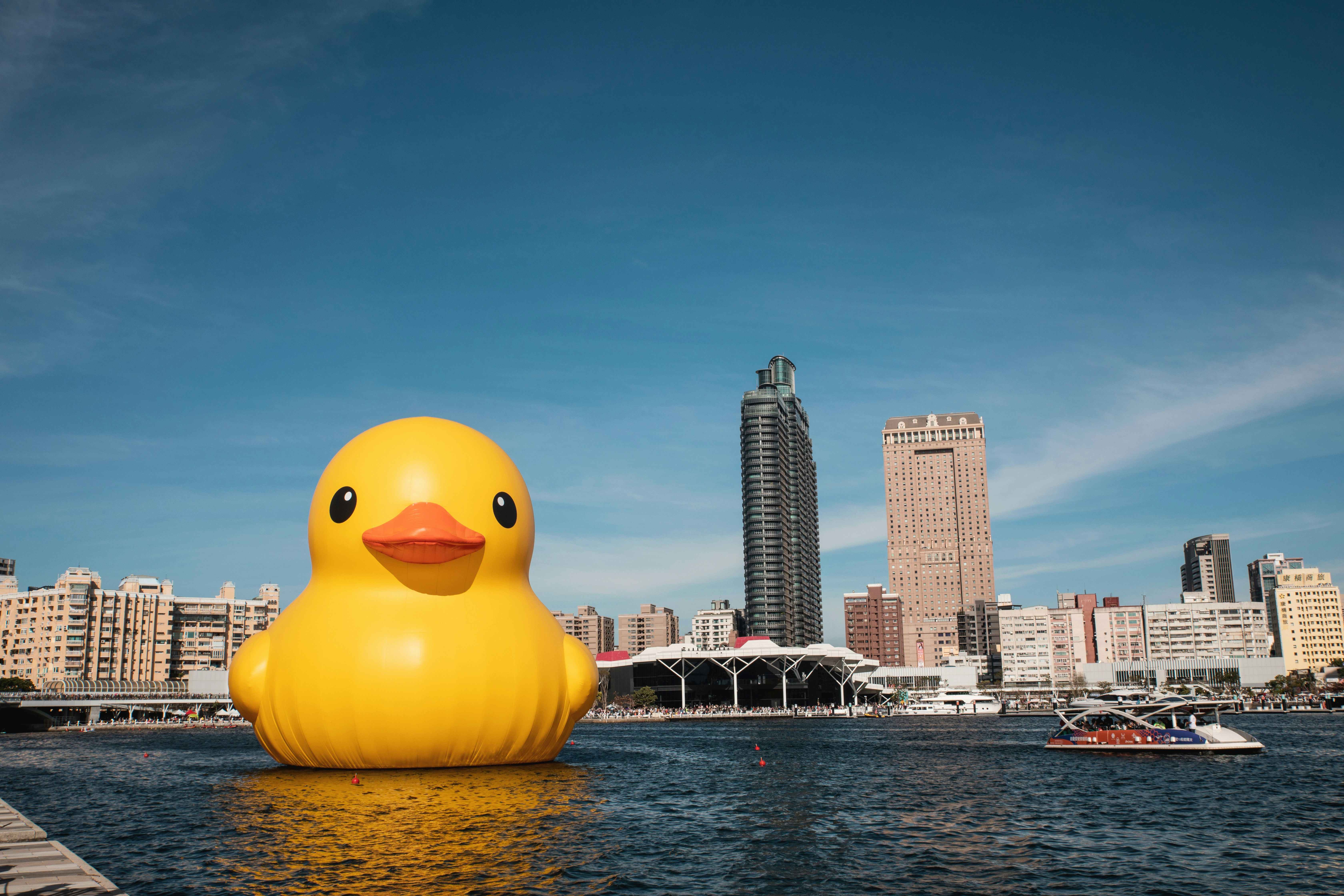 A large yellow rubber duck floating on top of a body of water photo ...